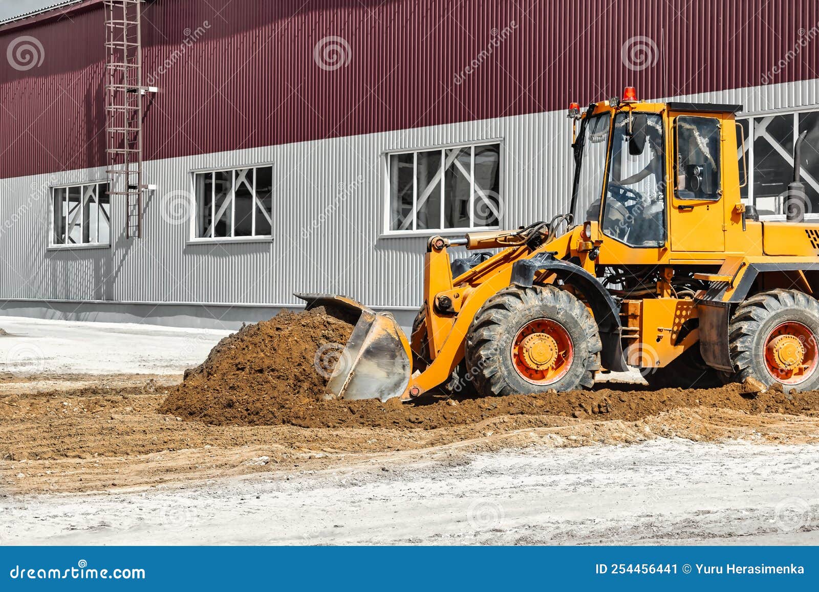 A Large Front Loader Pours Sand into a Pile at a Construction Site ...