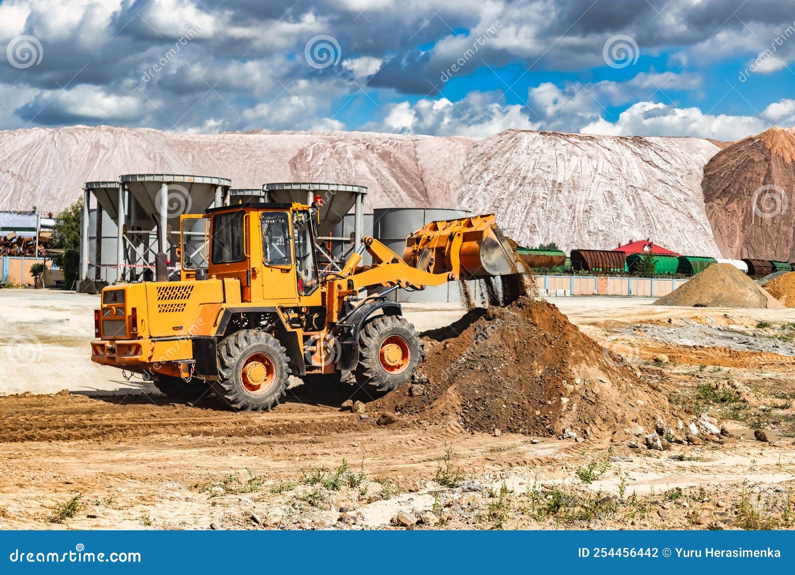 A Large Front Loader Pours Sand into a Pile at a Construction Site ...