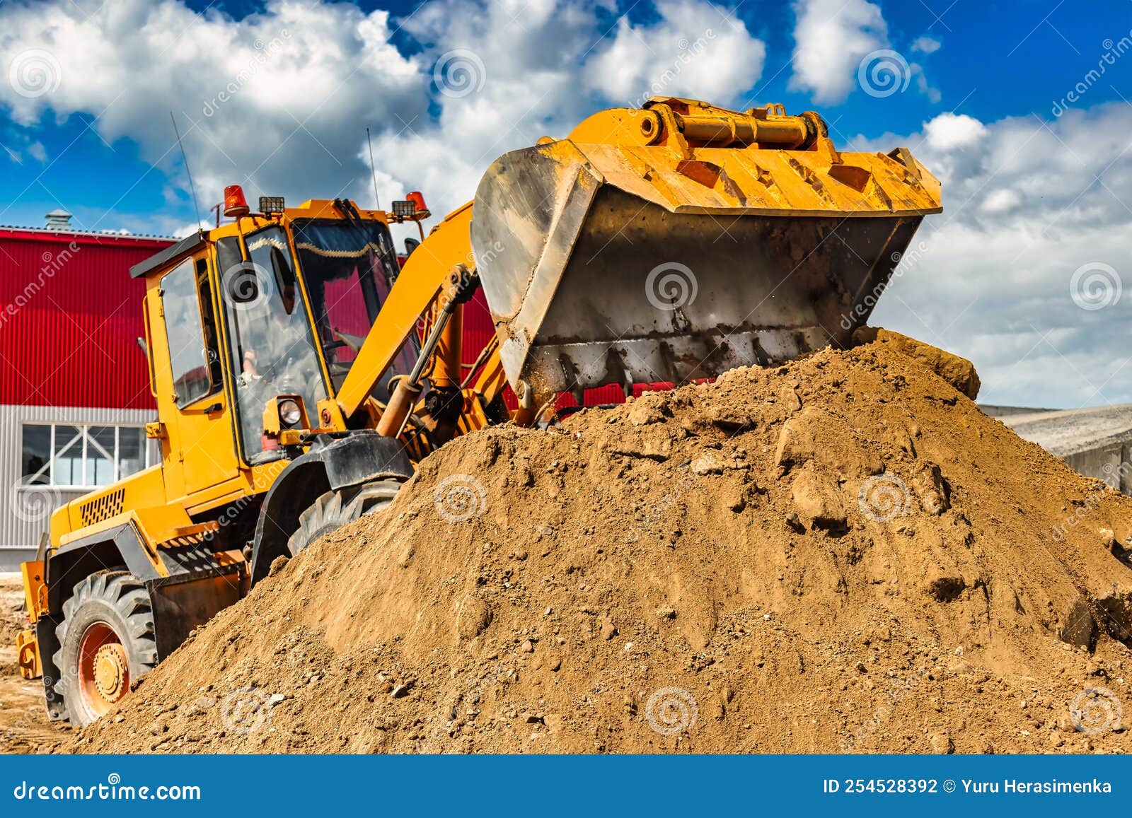 A Large Front Loader Pours Sand into a Pile at a Construction Site ...