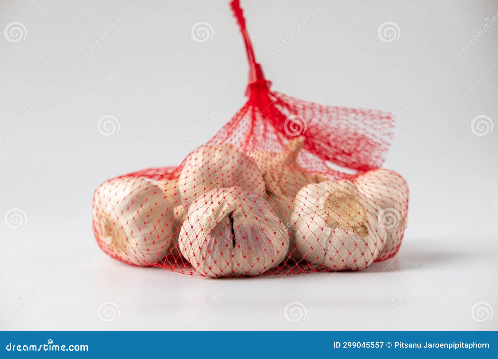 A Large Head of Garlic is in a Red Mesh Package on a White Background ...