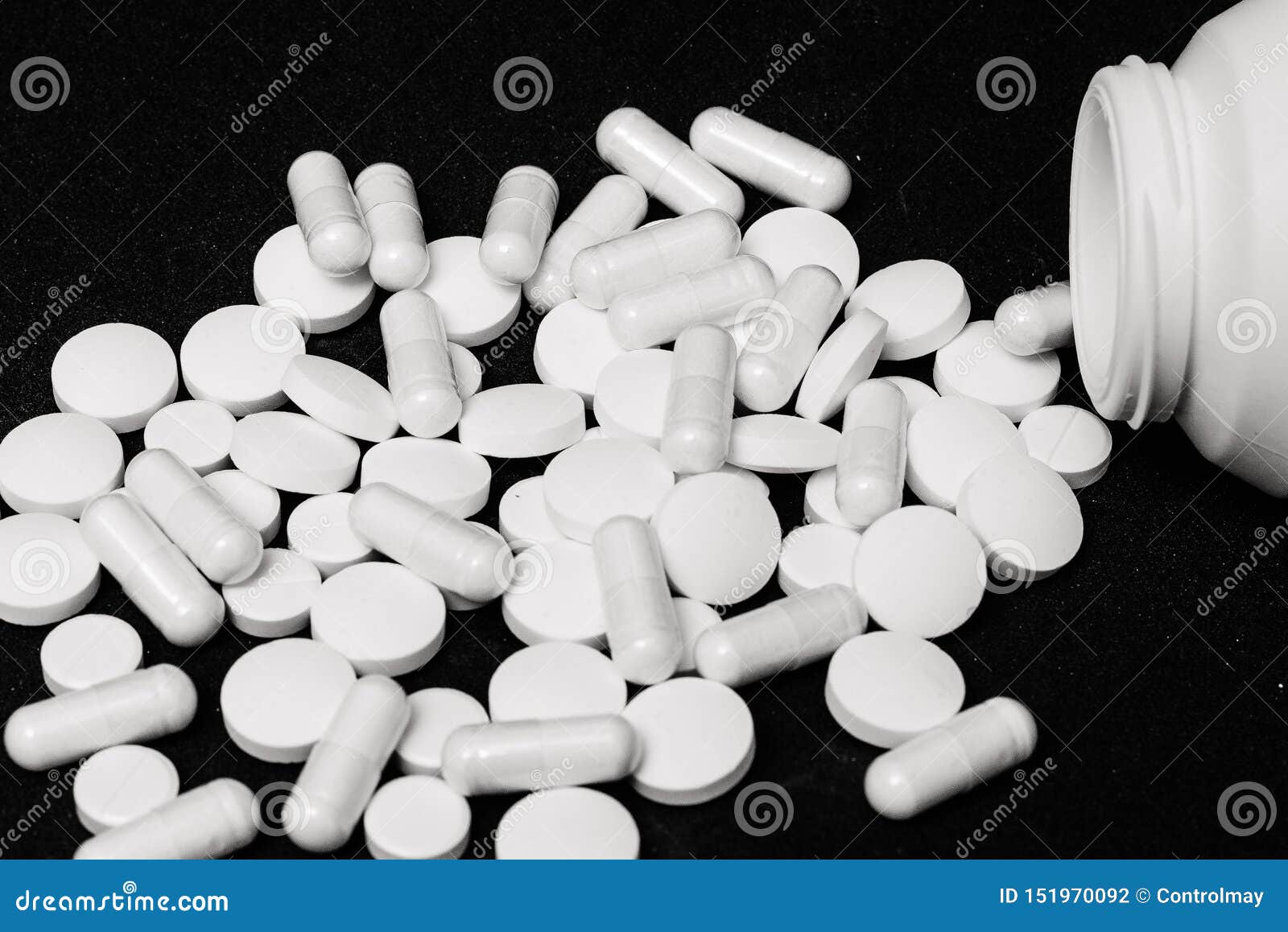A Large Number of White Tablets Scattered from the Container on a Black ...