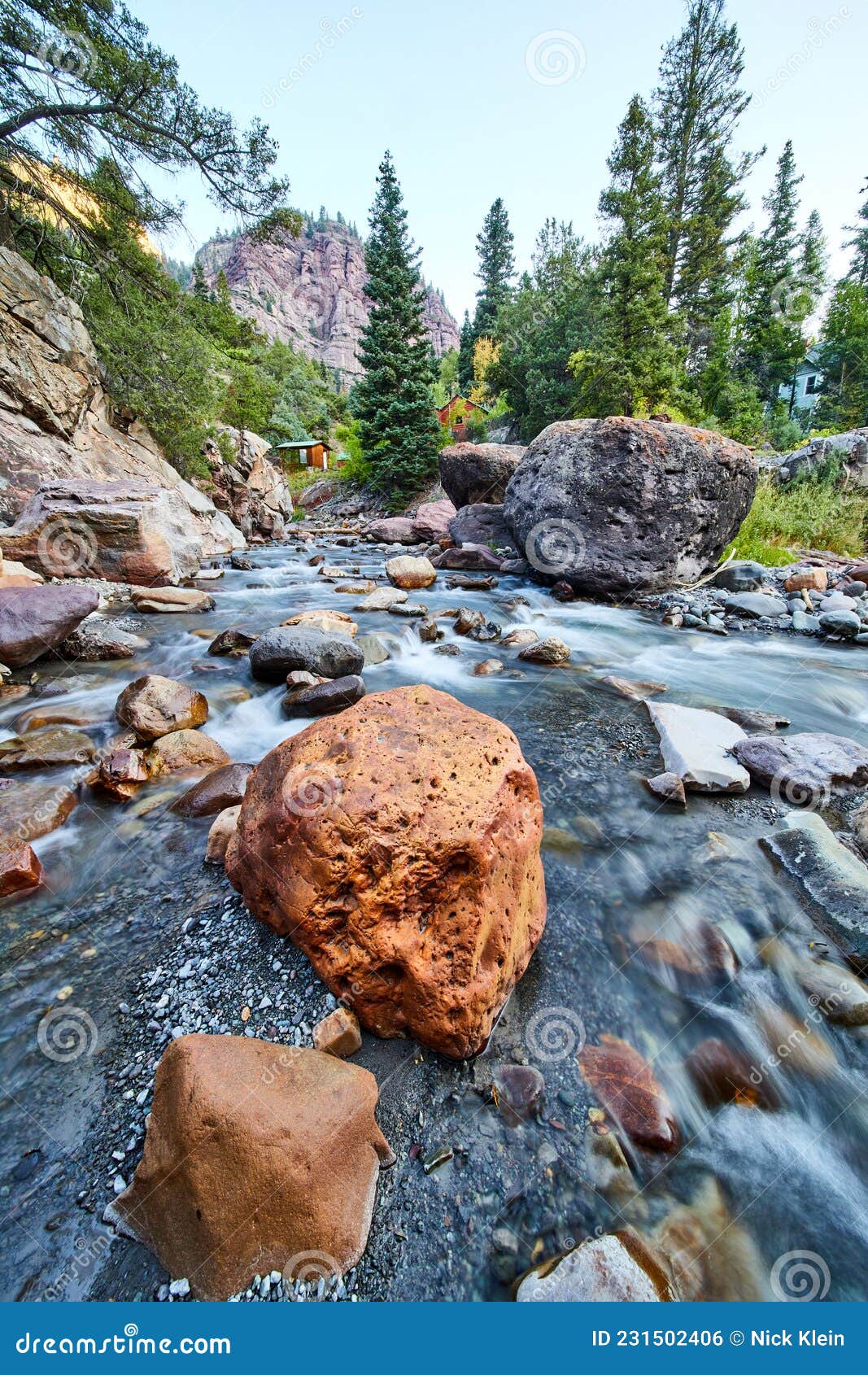 Large Red Rock in Clear Shallow Riverbed with Mountain in Distance ...