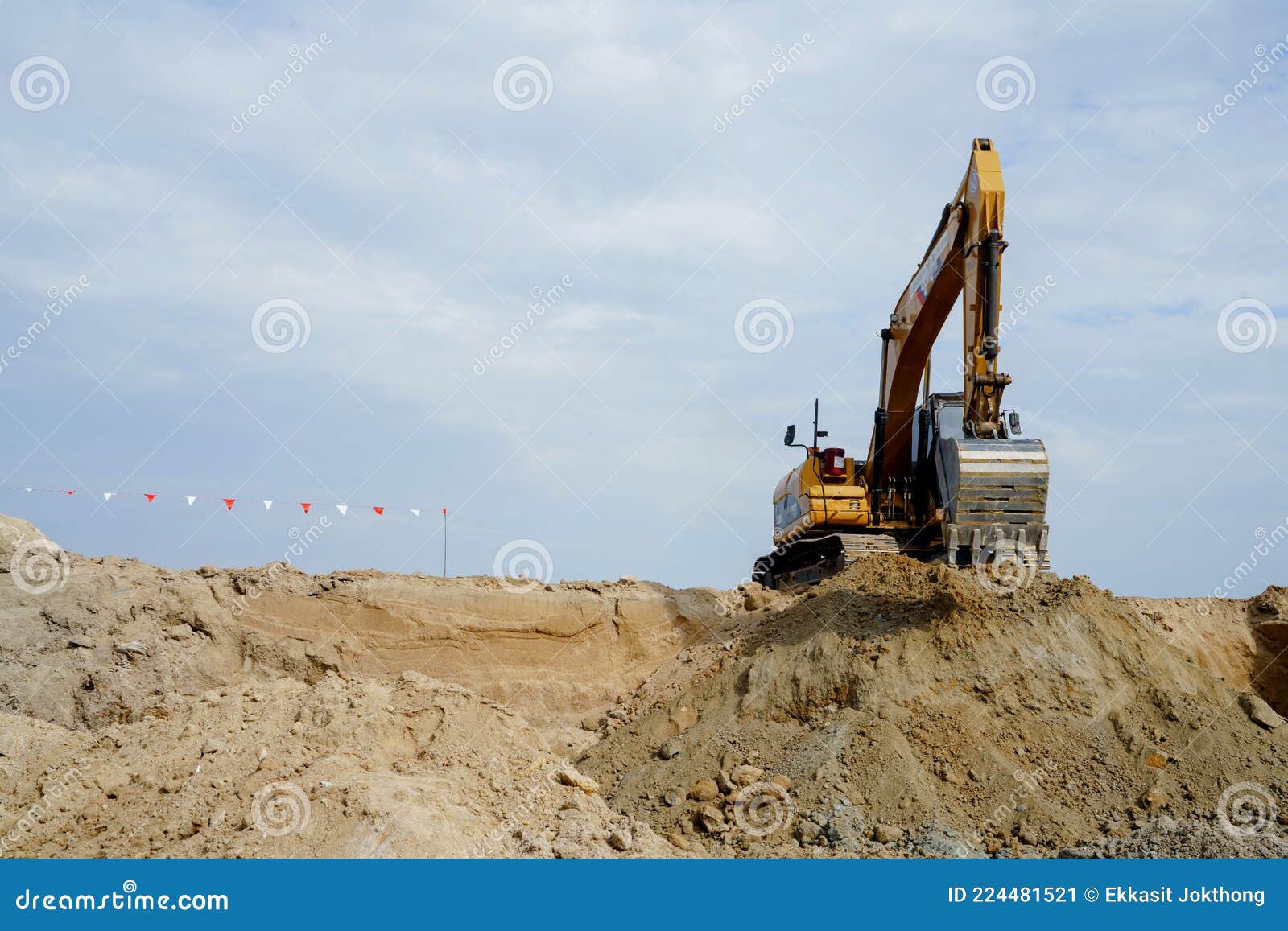 A Large Yellow Backhoe is Planting and Grading Brown Rays in a Factory ...