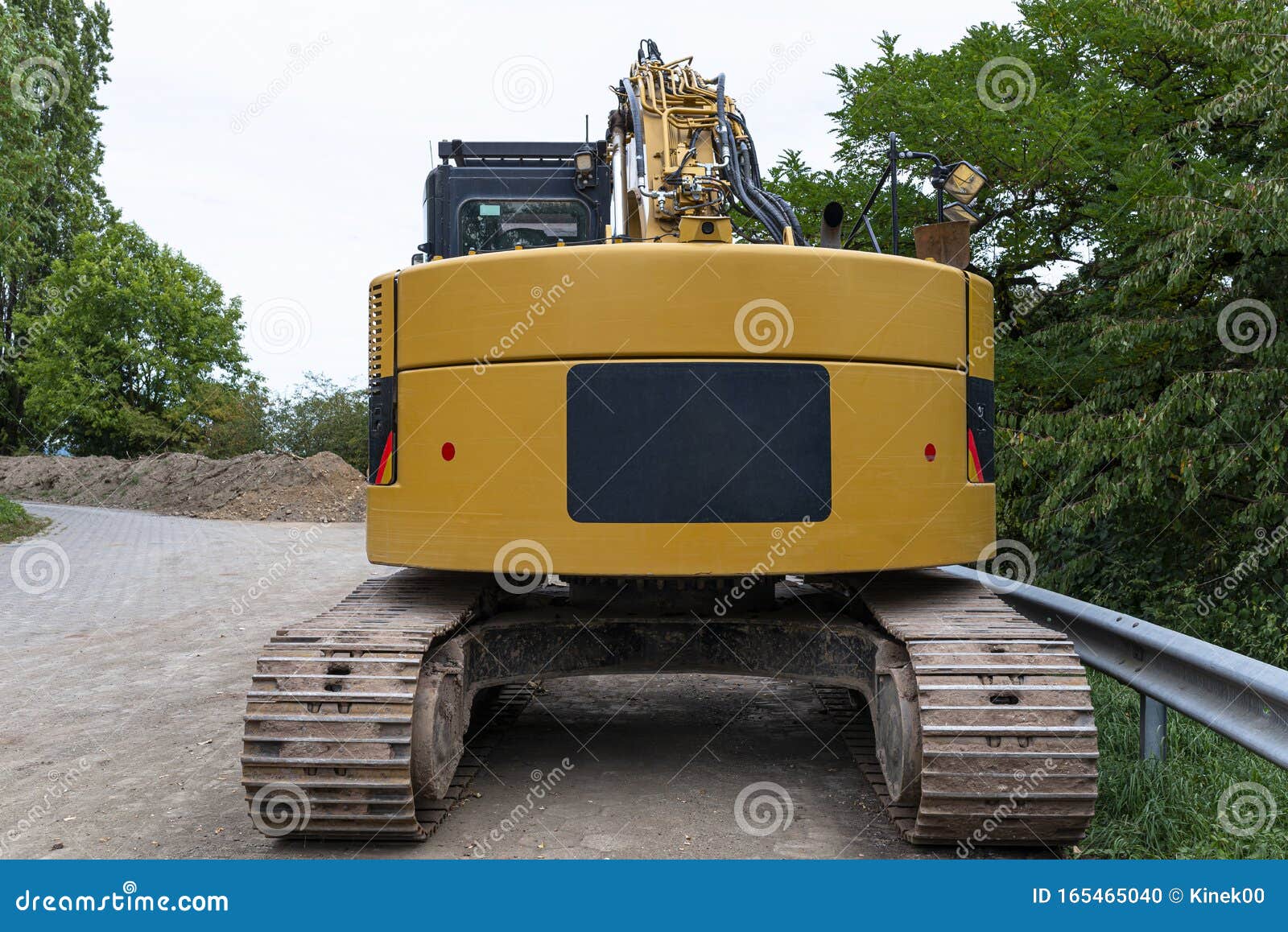 A Large Yellow Excavator Visible from the Rear, Standing on Concrete ...