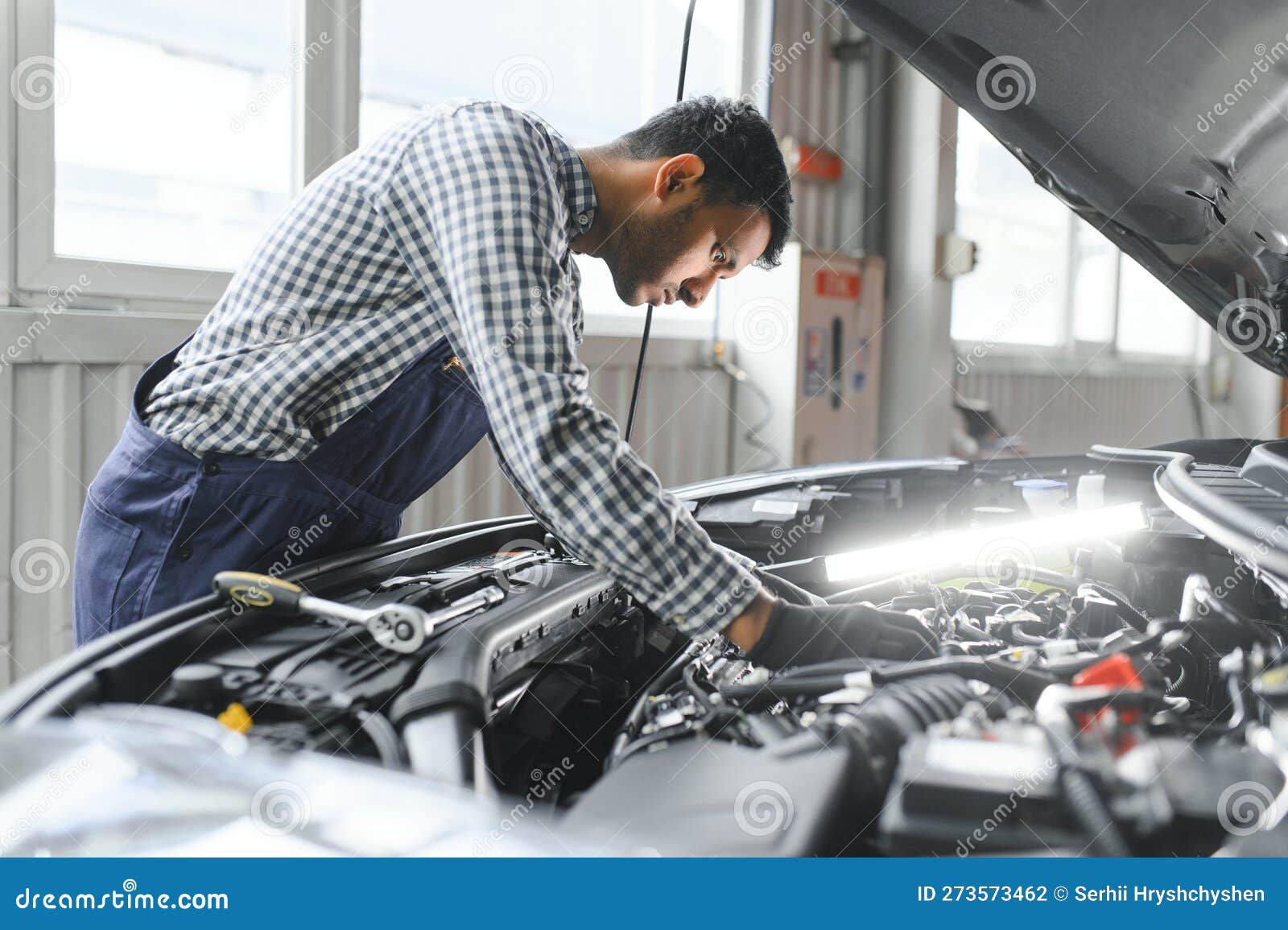 Latin Hispanic Auto Mechanic in Uniform is Examining a Car while ...