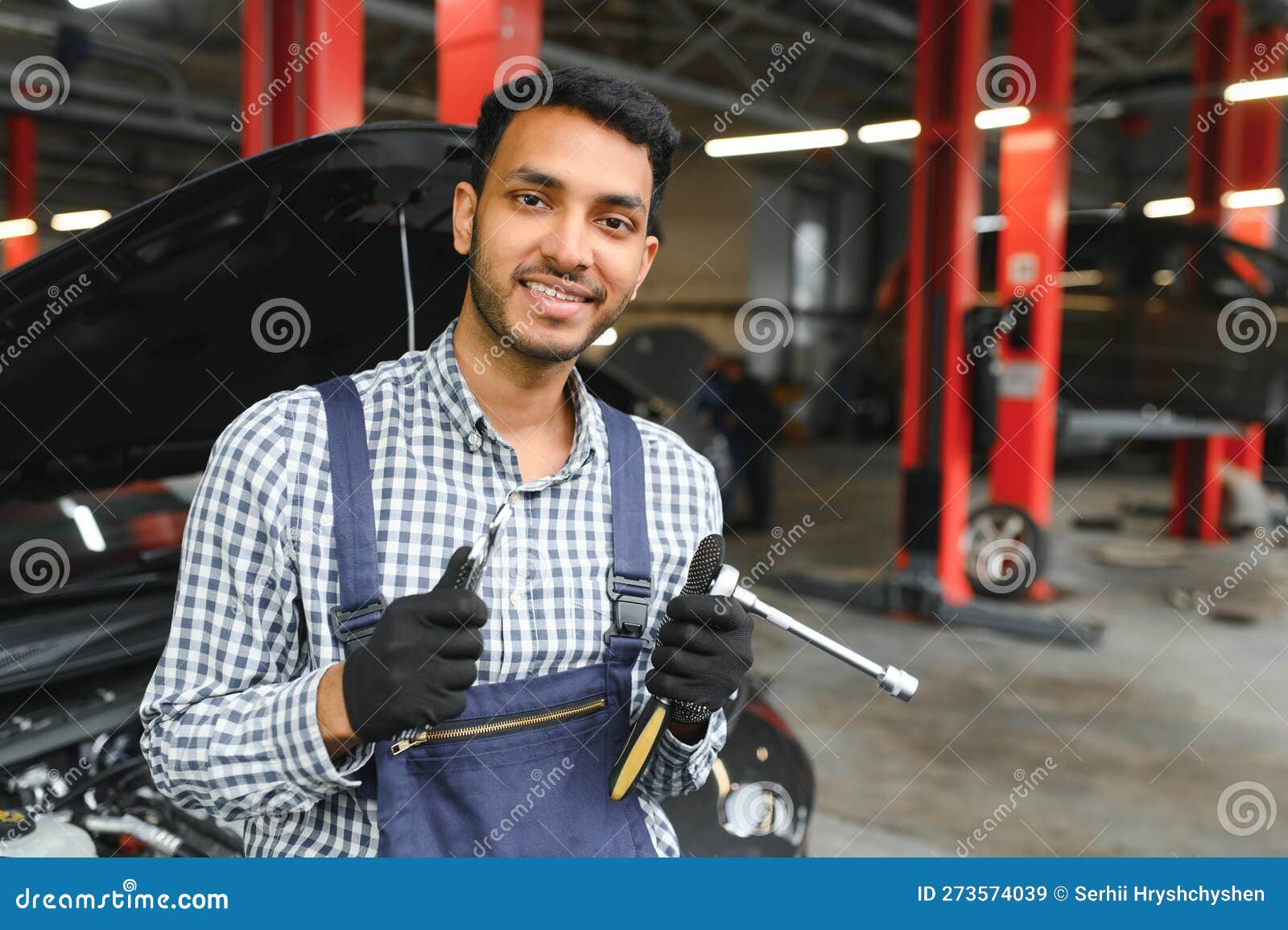 Latin Hispanic Auto Mechanic in Uniform is Examining a Car while ...