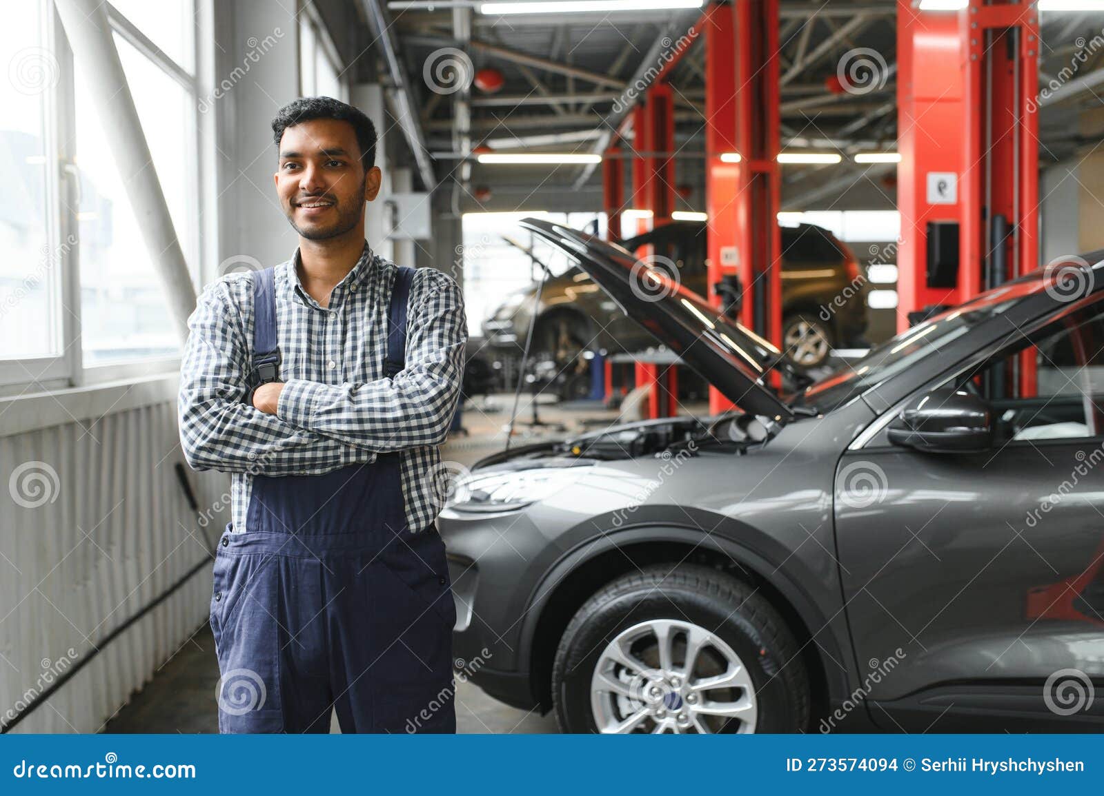 Latin Hispanic Auto Mechanic in Uniform is Examining a Car while ...