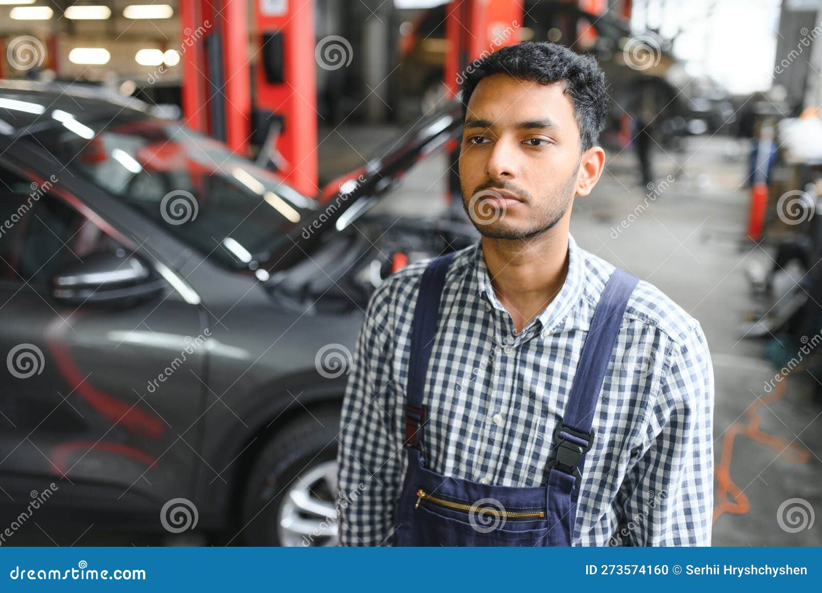 Latin Hispanic Auto Mechanic in Uniform is Examining a Car while ...