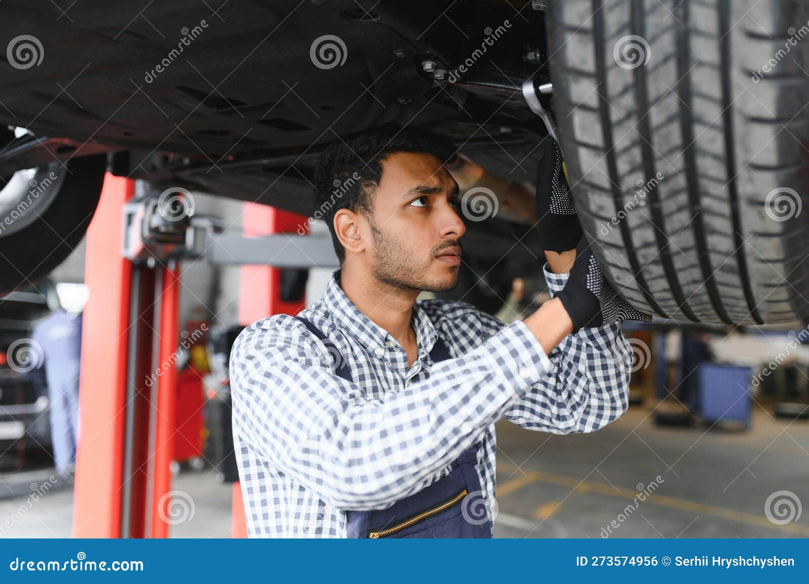 Latin Hispanic Auto Mechanic in Uniform is Examining a Car while ...