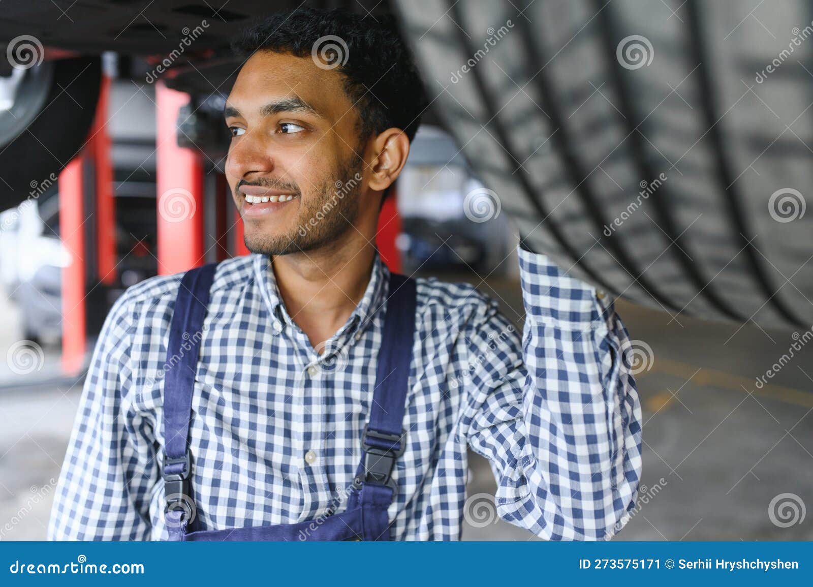Latin Hispanic Auto Mechanic in Uniform is Examining a Car while ...