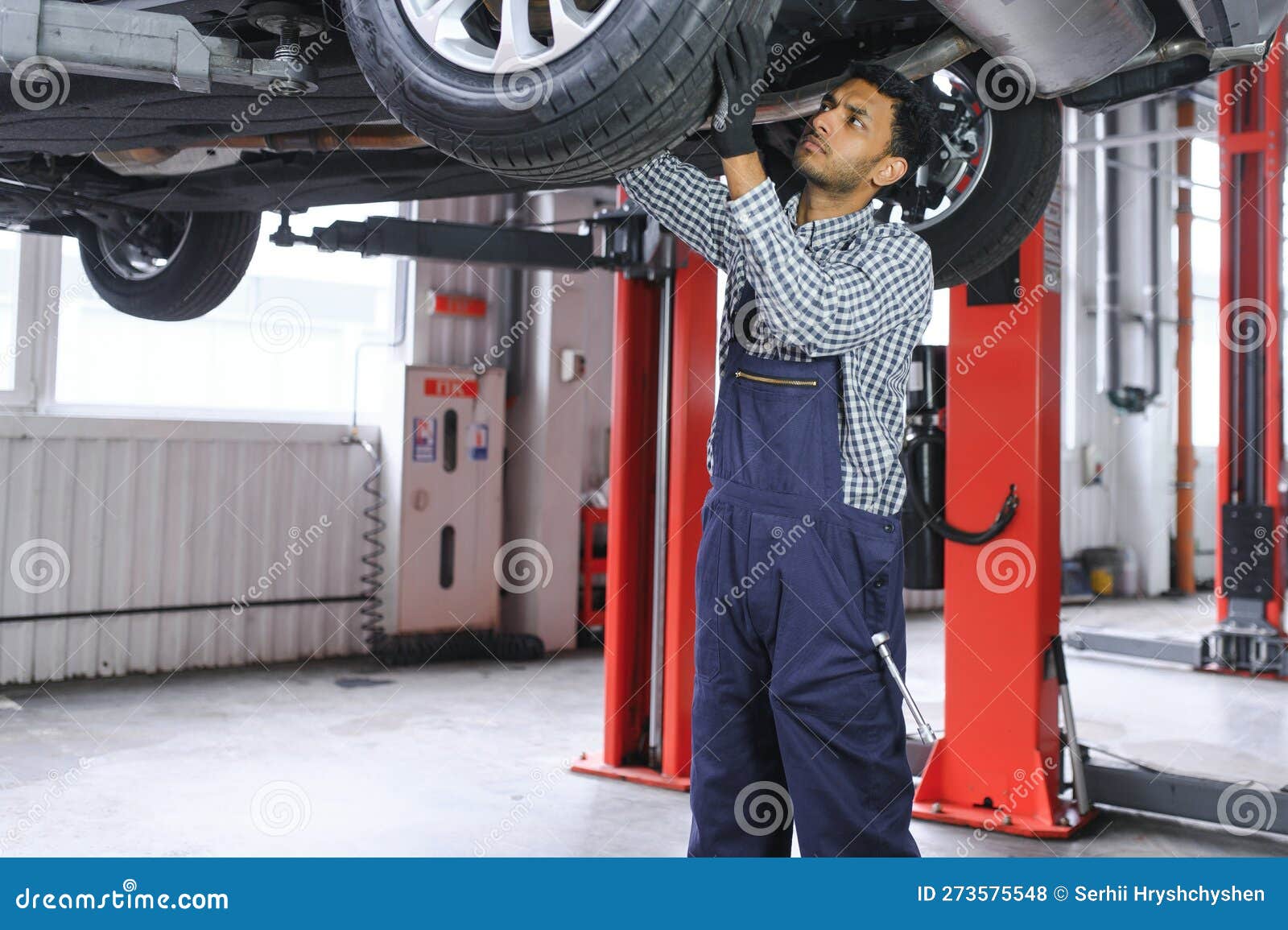 Latin Hispanic Auto Mechanic in Uniform is Examining a Car while ...