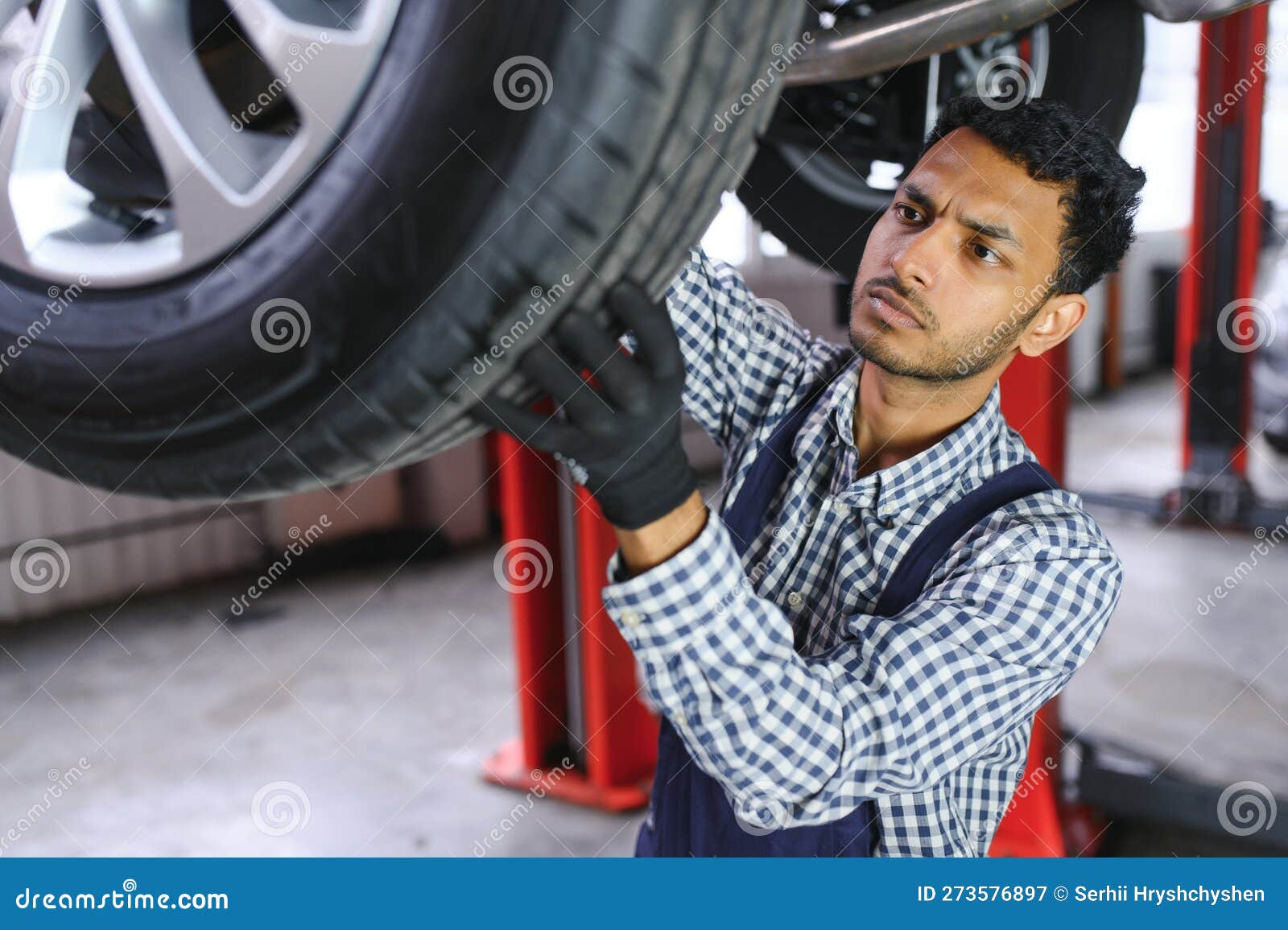 Latin Hispanic Auto Mechanic in Uniform is Examining a Car while ...