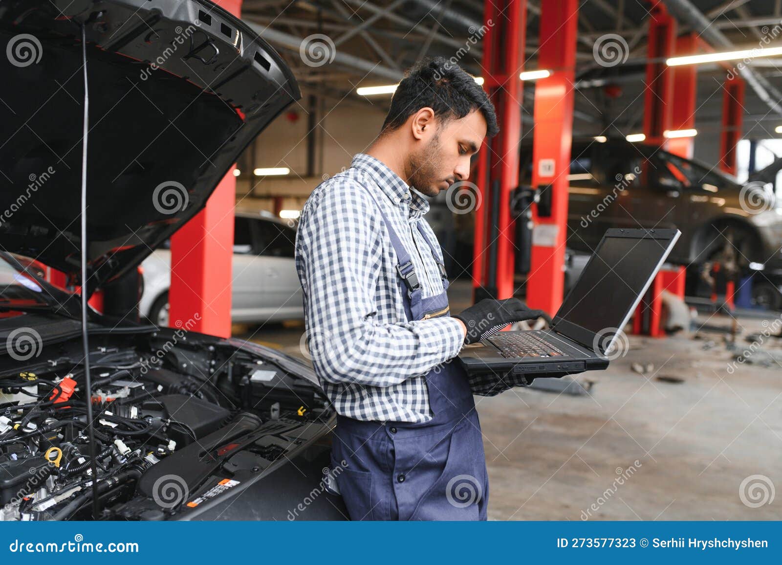 Latin Hispanic Auto Mechanic in Uniform is Examining a Car while ...