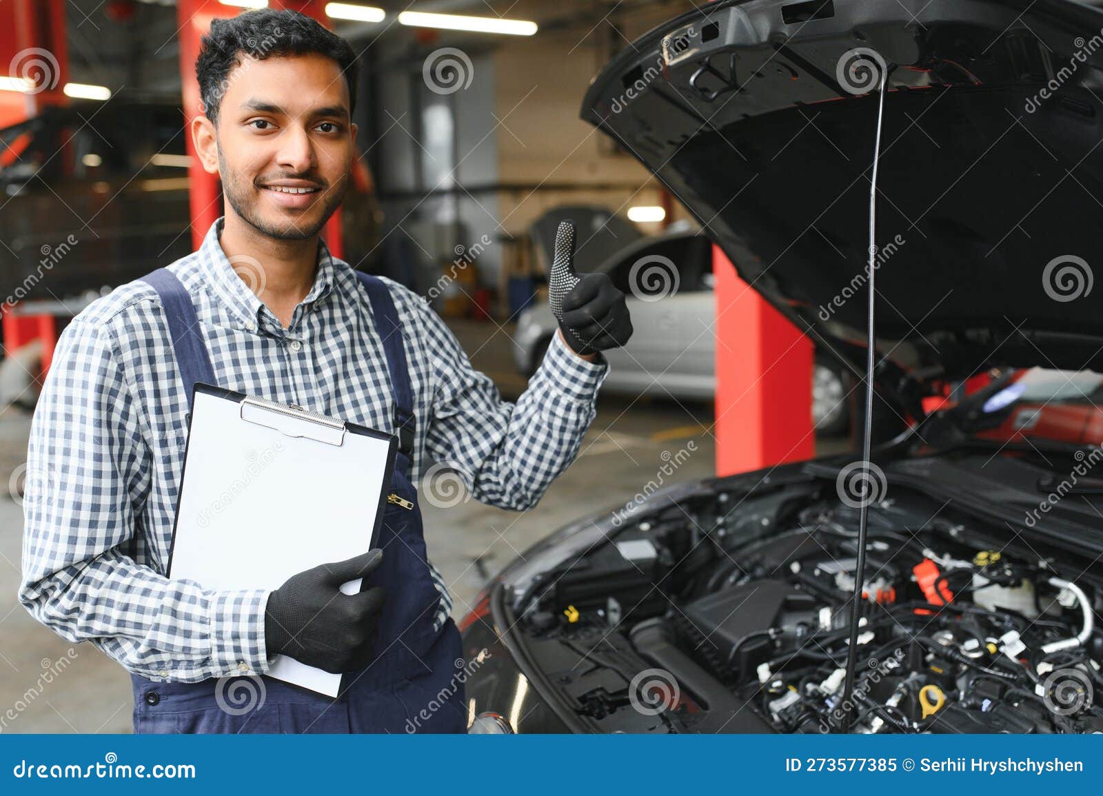 Latin Hispanic Auto Mechanic in Uniform is Examining a Car while ...