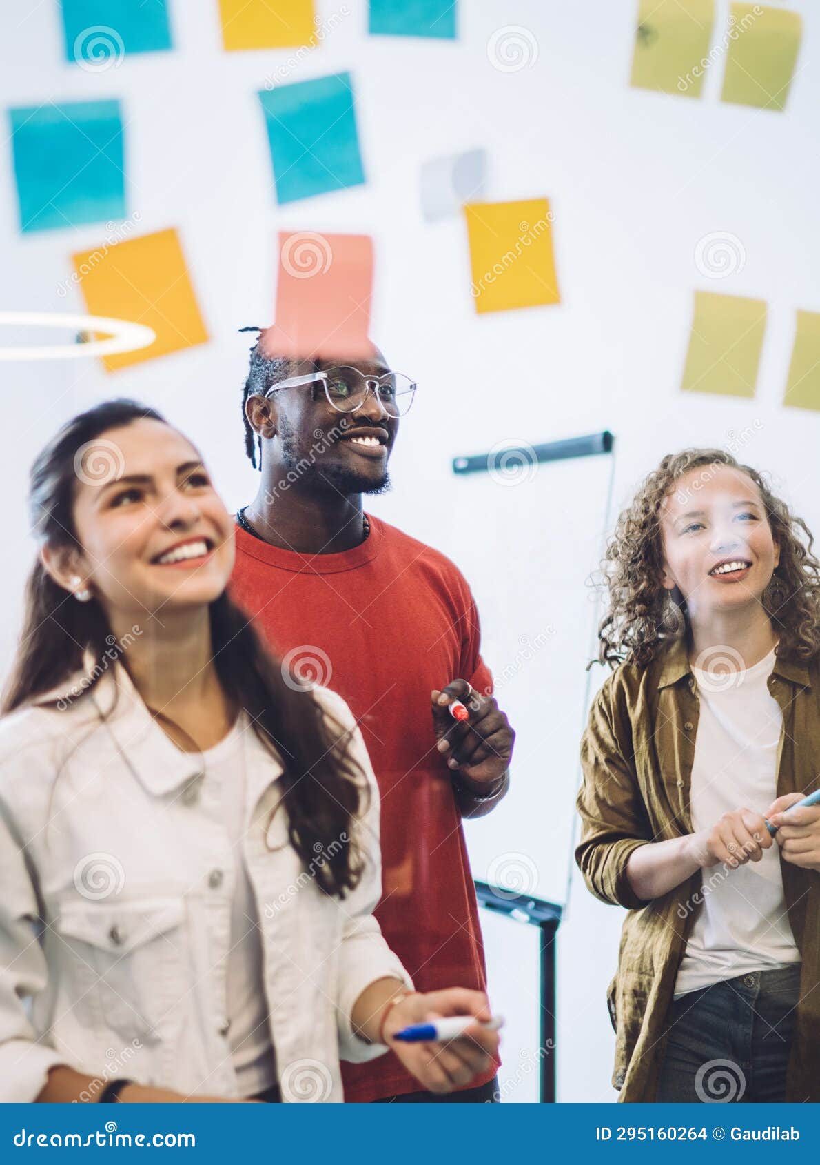 Laughing Coworkers Placing Notes on Glass Wall Stock Photo - Image of ...