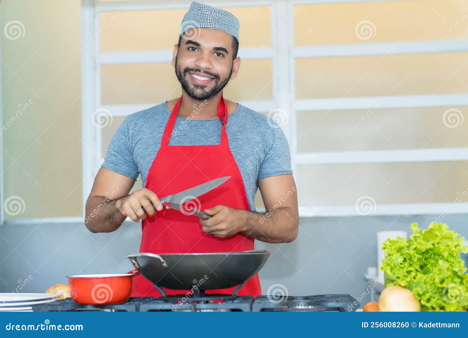 Laughing Hispanic Cook with Red Apron Preparing Food at Kitchen Stock ...