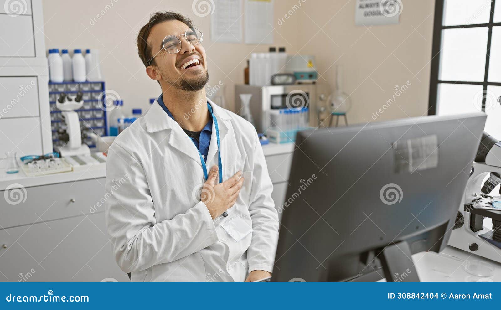 Laughing Hispanic Man in Lab Coat Sitting at Computer in Bright ...