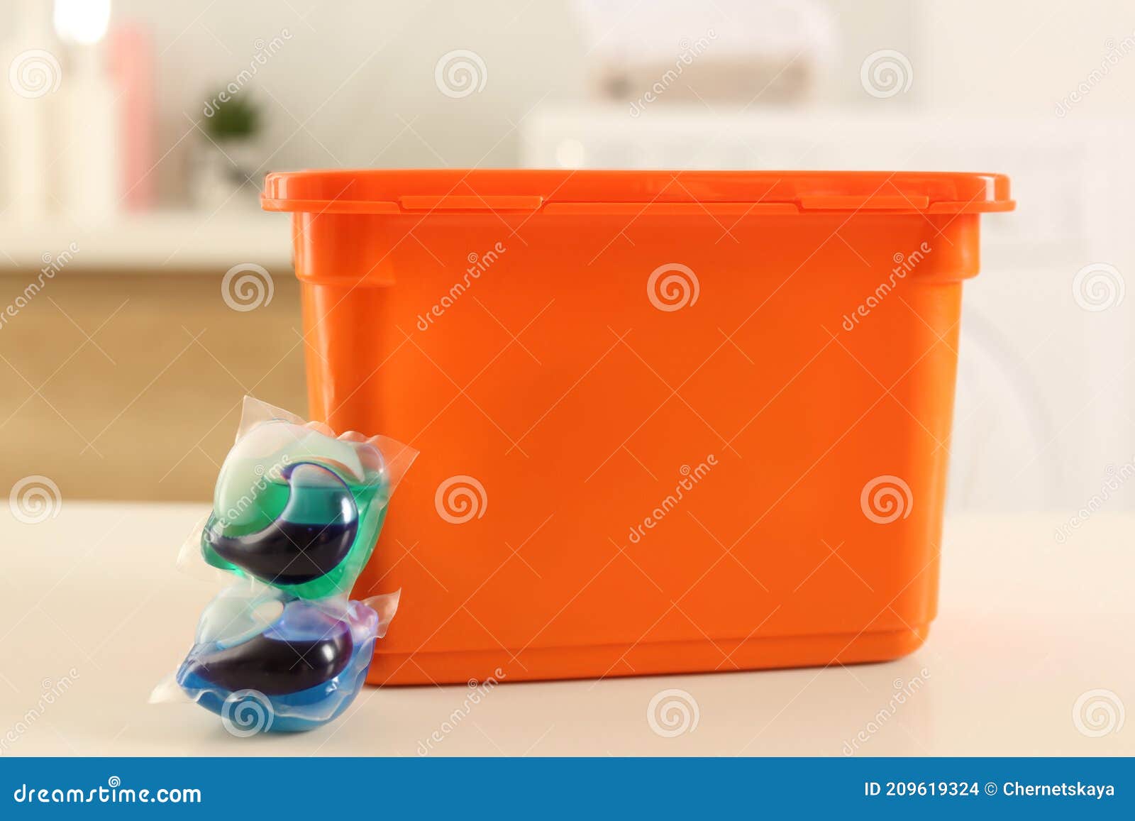 Laundry Container and Washing Detergent Capsules on Table Indoors Stock ...