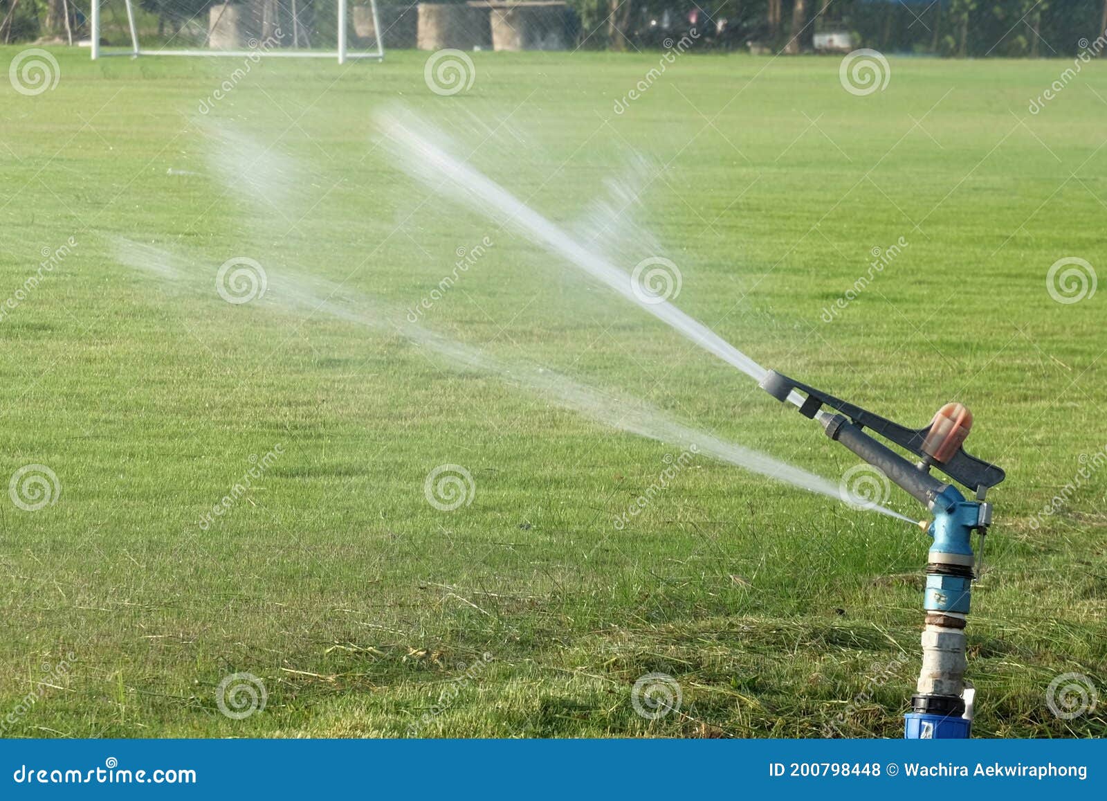 Lawn Water Sprinkler in Action Spraying Water in Field Stock Photo ...