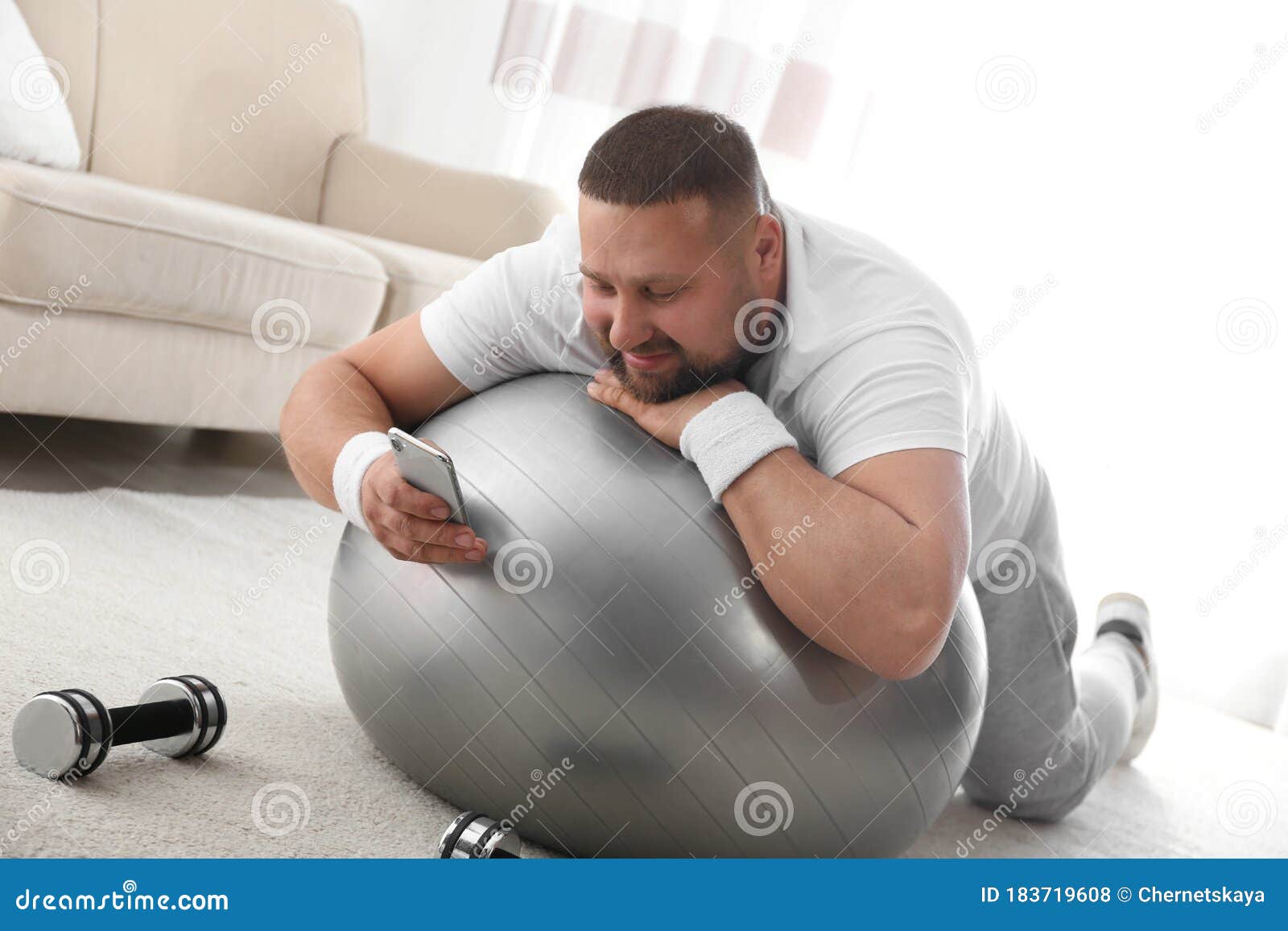 Lazy Overweight Man Using Smartphone while Lying on Exercise Ball Stock ...