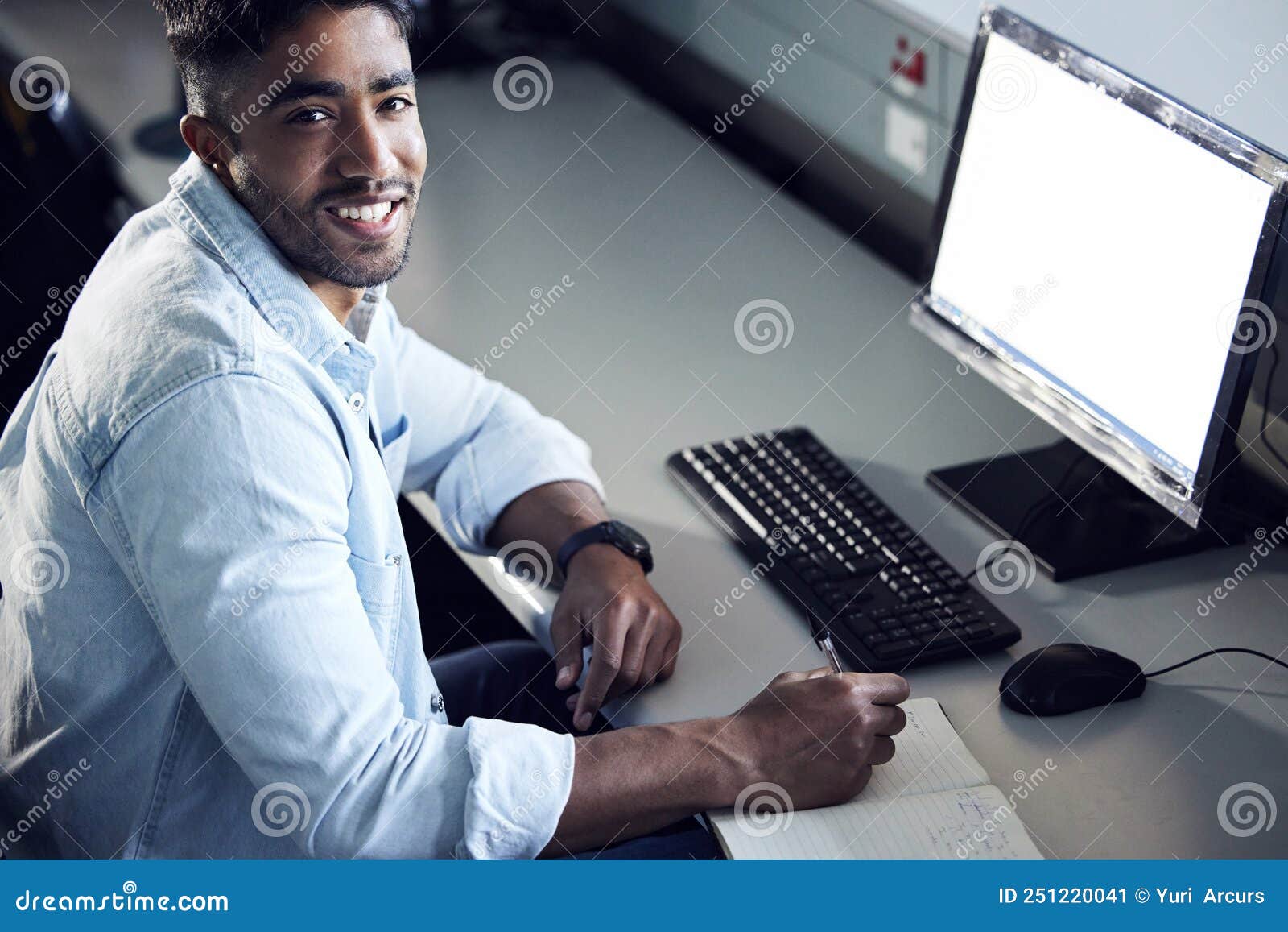 Learning All Things it. a Young Man Writing in a Notebook and Using a ...