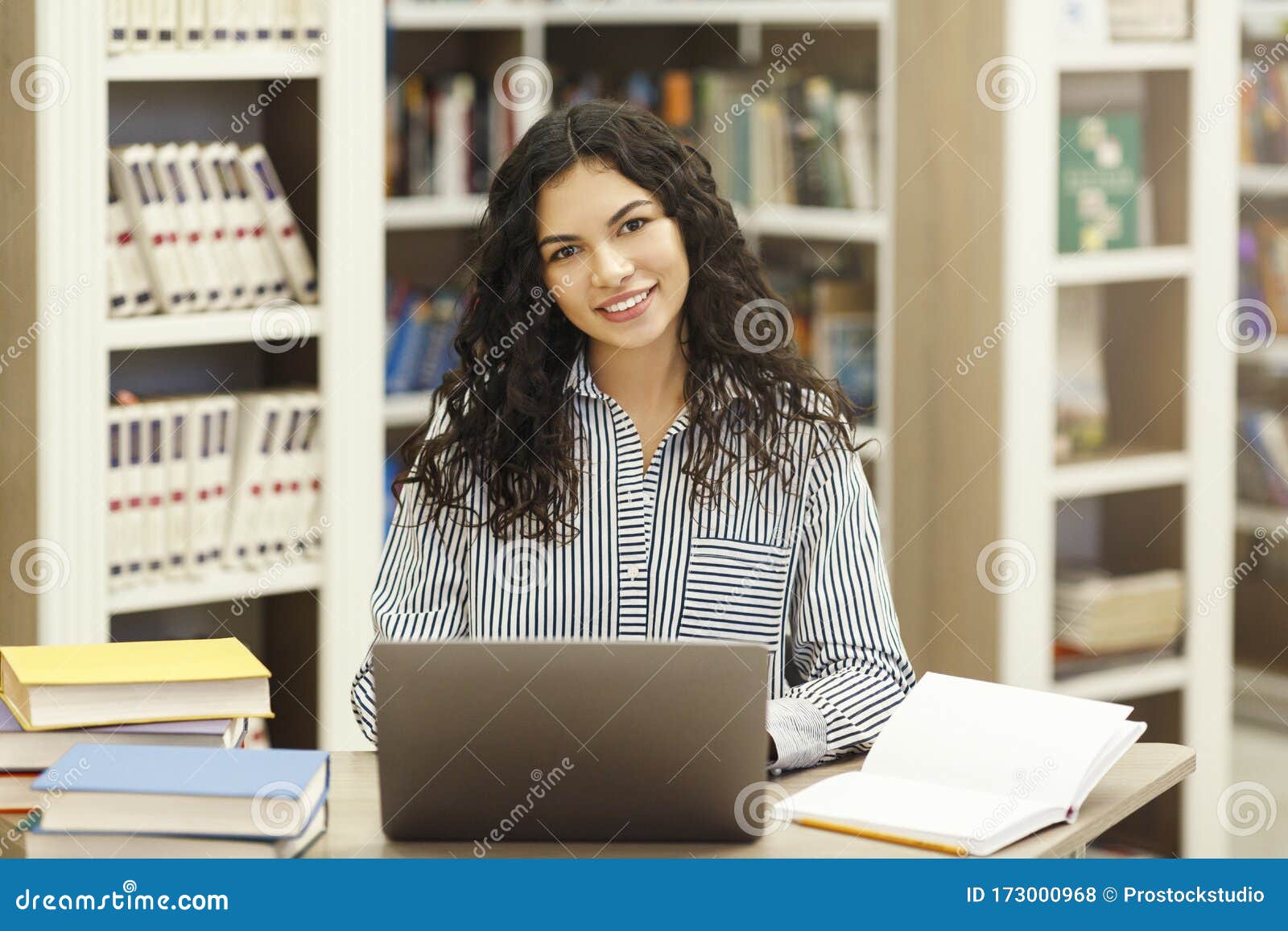 Confident Latina Girl Using Laptop in Modern Library Stock Photo ...