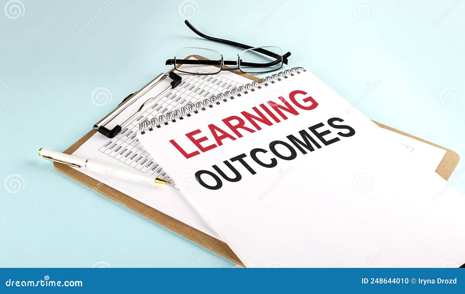 LEARNING OUTCOMES Text on Notepad on Clipboard with Chart on Blue ...