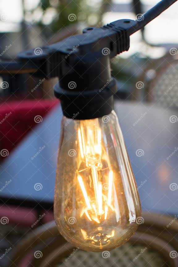 LED Bulb Hanging on the Background of Chairs and a Table, Restaurant ...