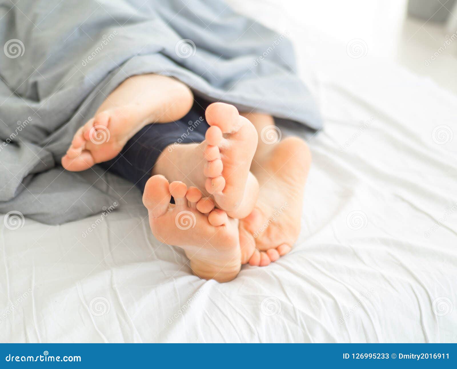 The Legs from Under the Blanket. Young Happy Couple in Bed at Home ...