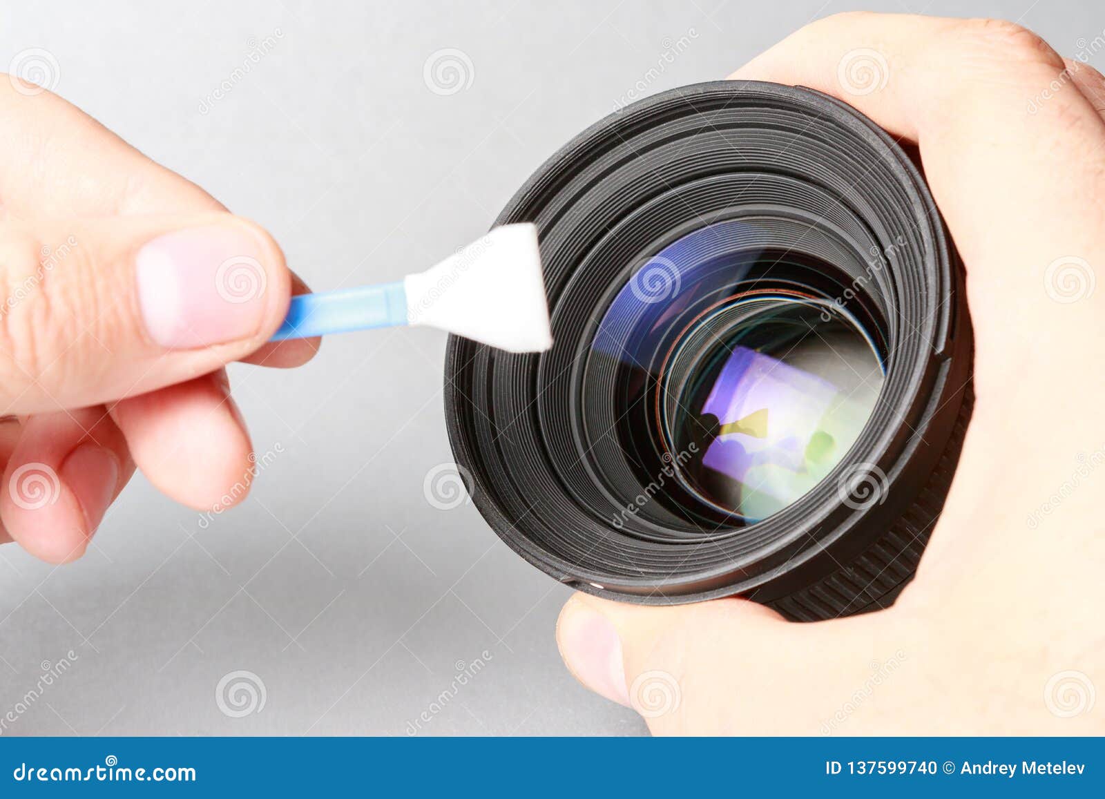 Lens in Hand, One Hand Holding the Lens Second Brushing with a Special ...