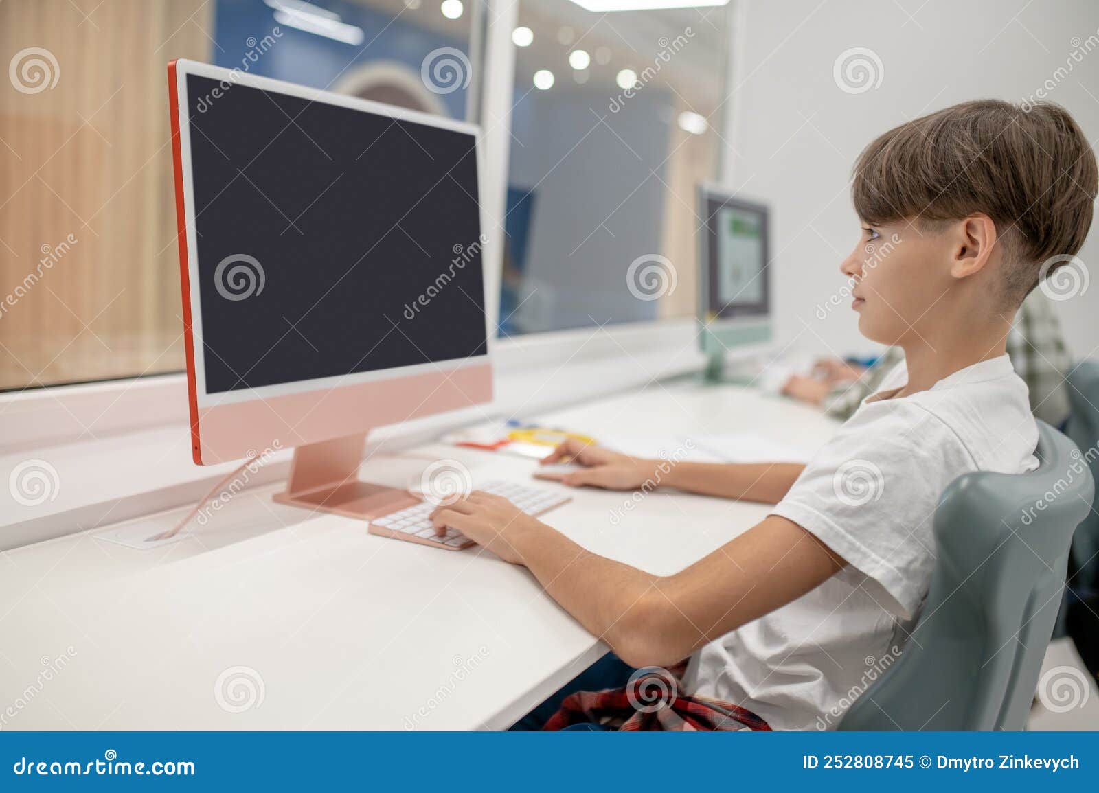 A Schoolboy Sitting at the Computer at School and Looking Involved ...
