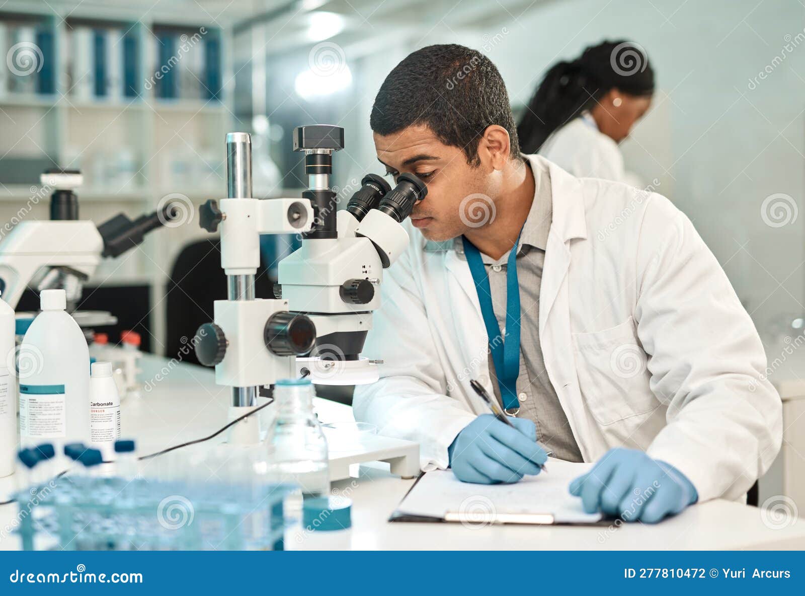 Lets Investigate Further. a Young Scientist Writing Notes while Using a ...