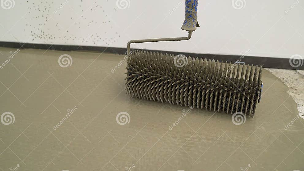 Leveling the Floor Using Spiked Roller. Construction Worker Mixes ...