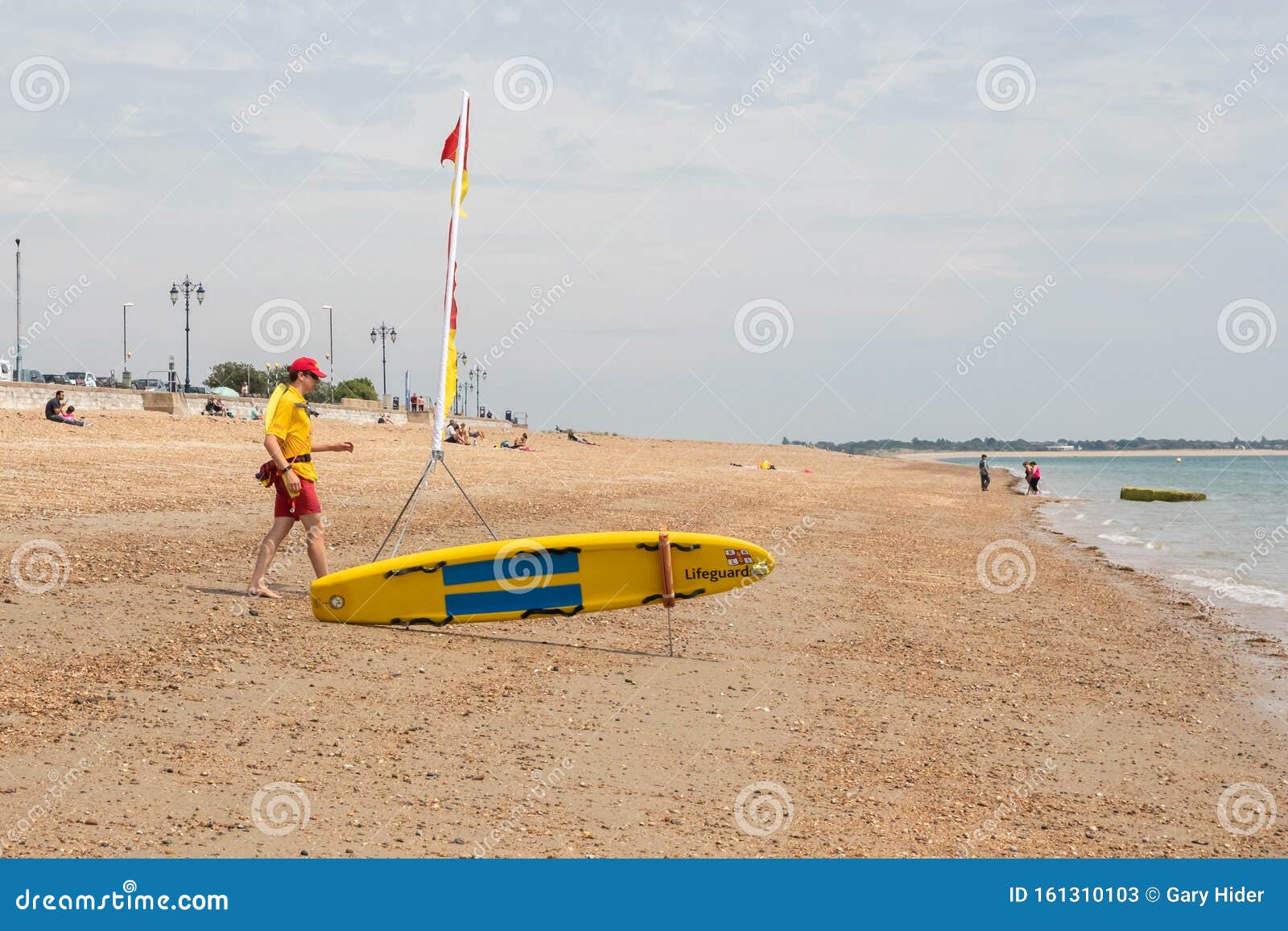 A Lifeguard Patrolling a British Pebble Beach with Surfboard and Red ...