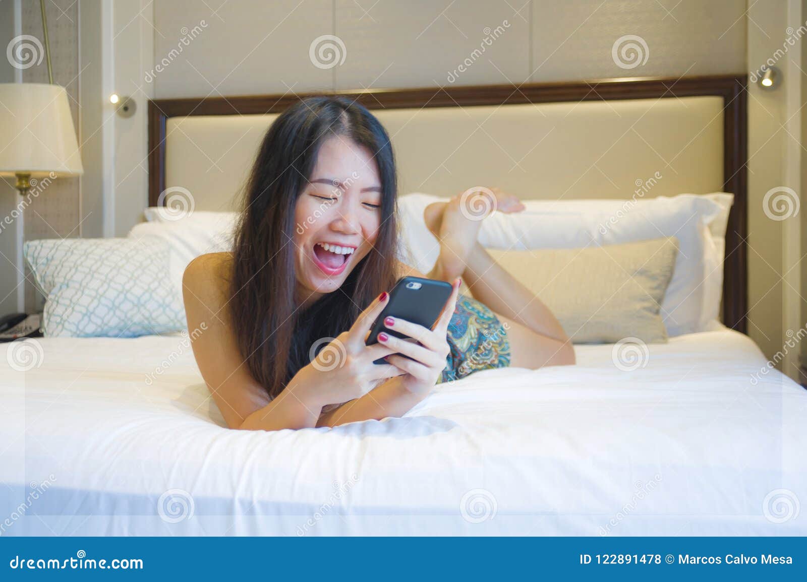 Young Happy Pretty Asian Korean Woman At Home Or Hotel Room Lying On