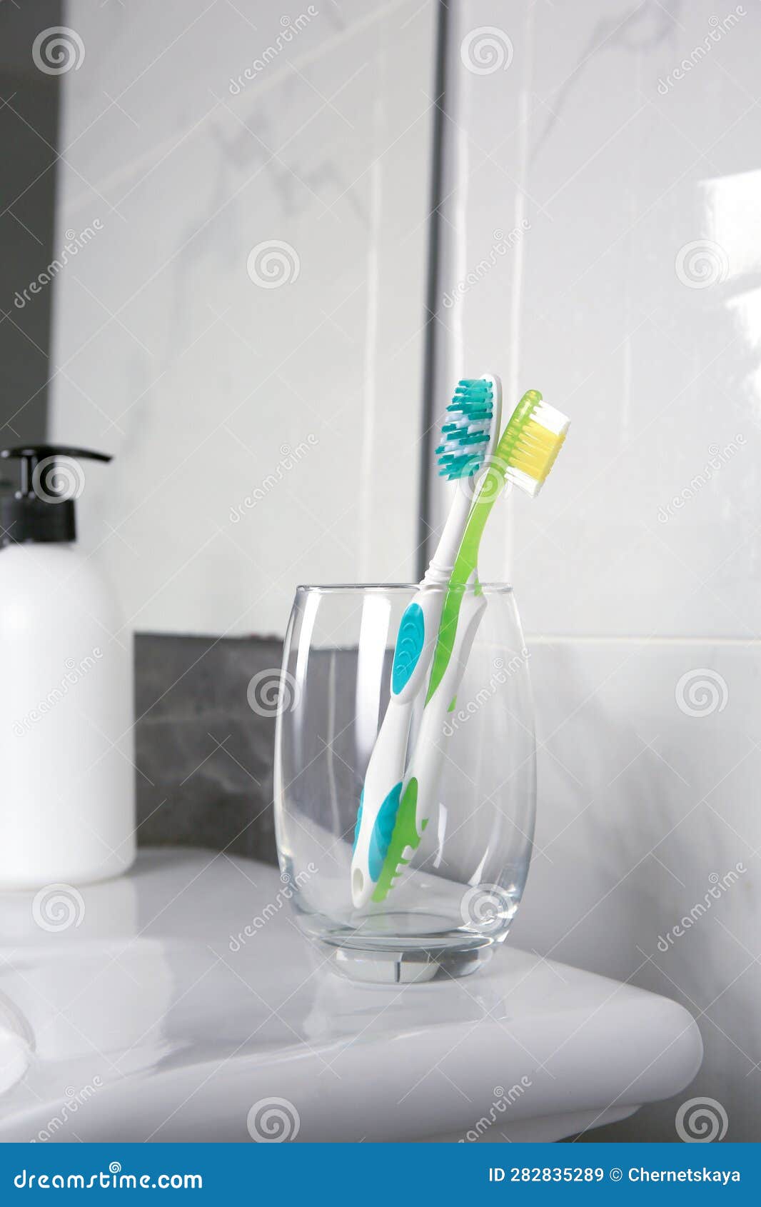 Light Blue and Green Toothbrushes in Glass Holder on Washbasin Stock ...