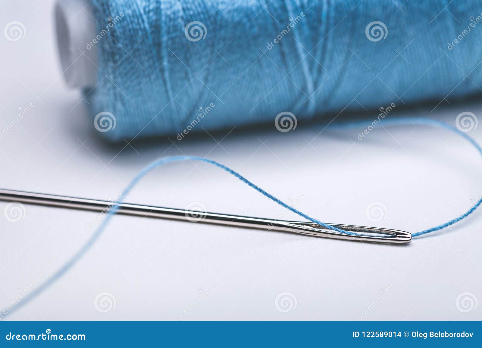 On the Light Surface, Blue Threads on Spool, Sewing Needle with Thread ...