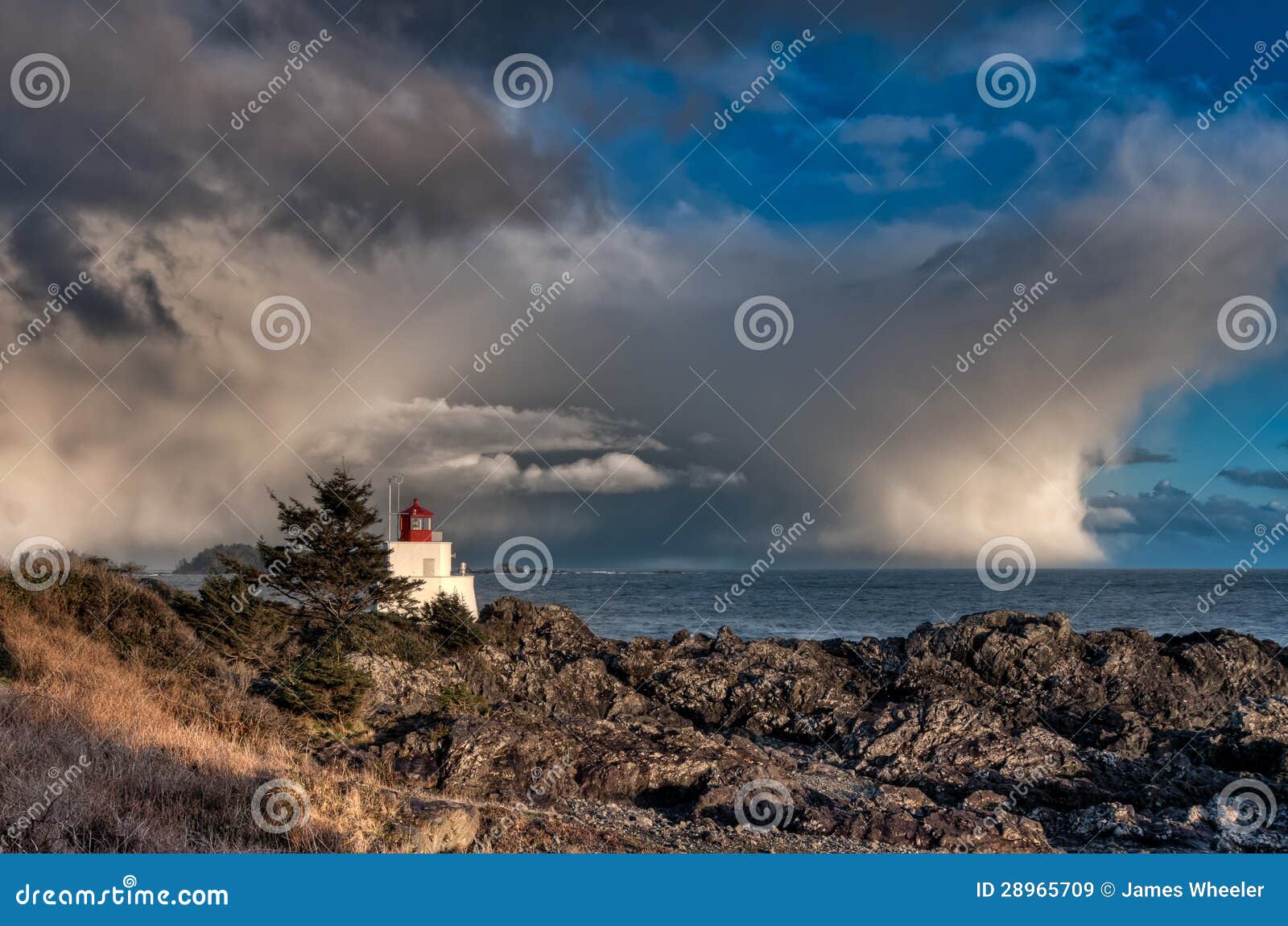 Lighthouse Along Rocky Shore with Storm Clouds in Distance Stock Image ...
