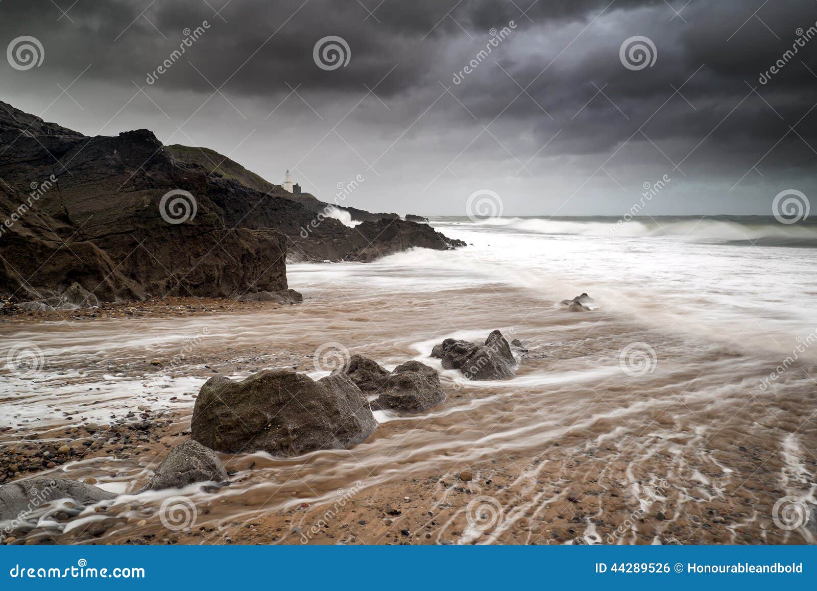 Lighthouse Landscape with Stormy Sky Over Sea with Rocks in Fore Stock ...