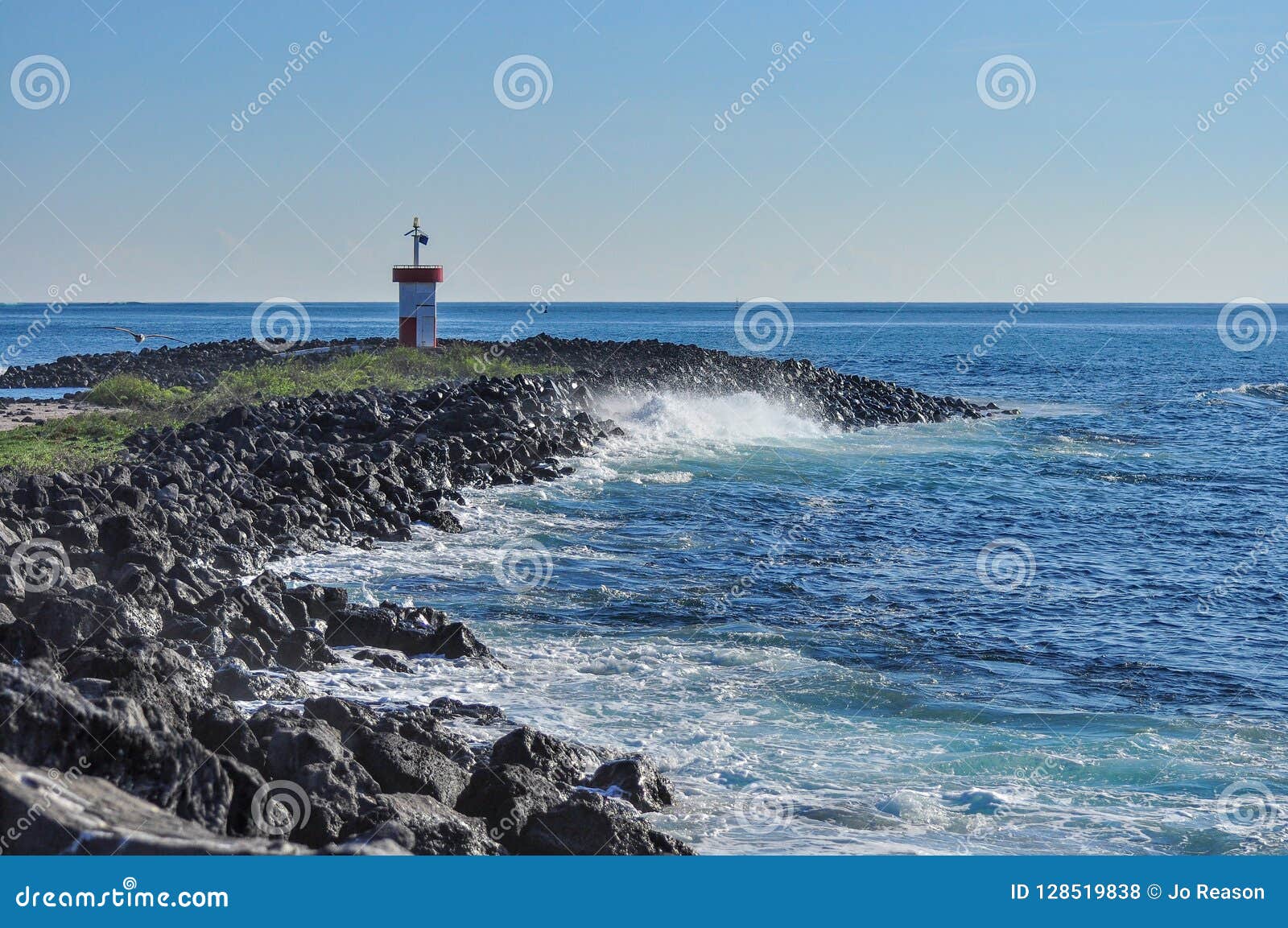 Lighthouse on the rocks stock photo. Image of sunny - 128519838