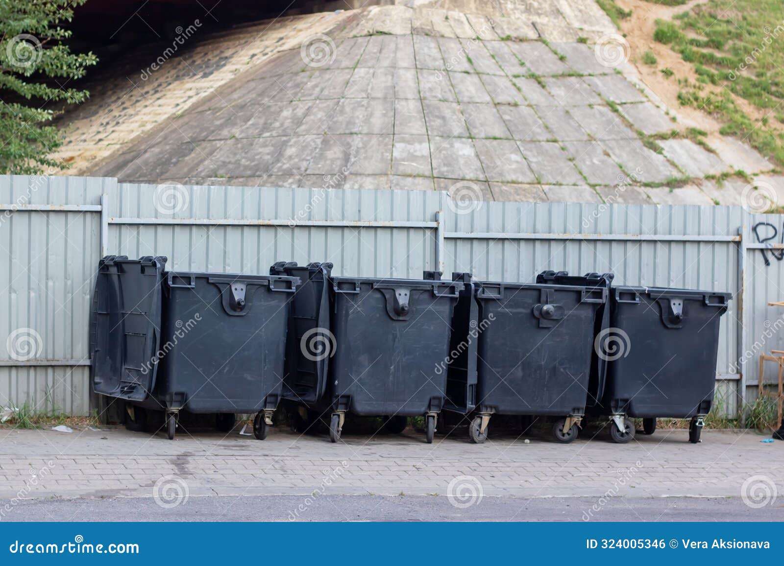 A Line of Black Trash Bins is Arranged in Front of a Barrier Stock ...