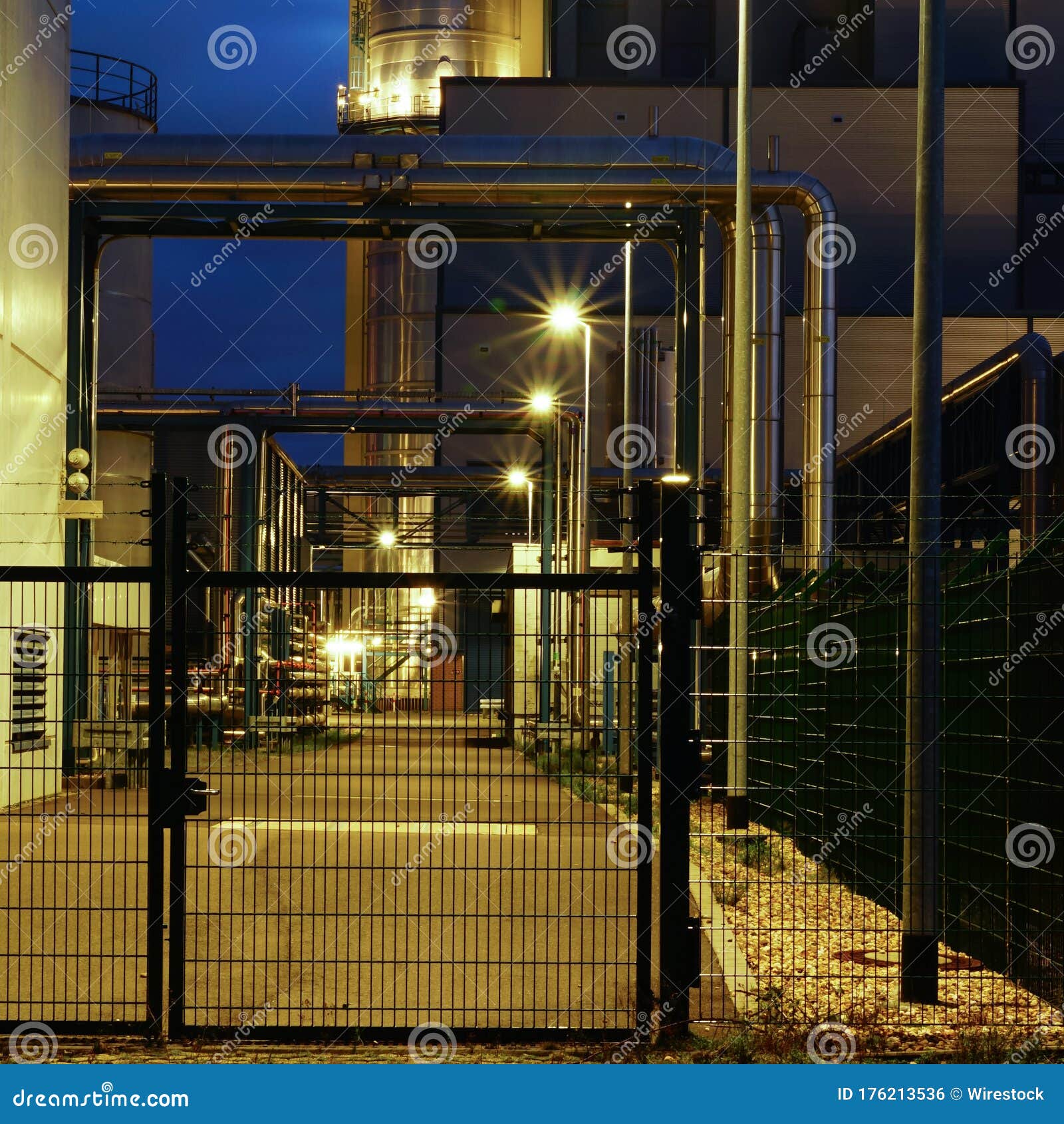Line of Lit Lamp Posts on an Alley Behind a Locked Gate Stock Photo ...