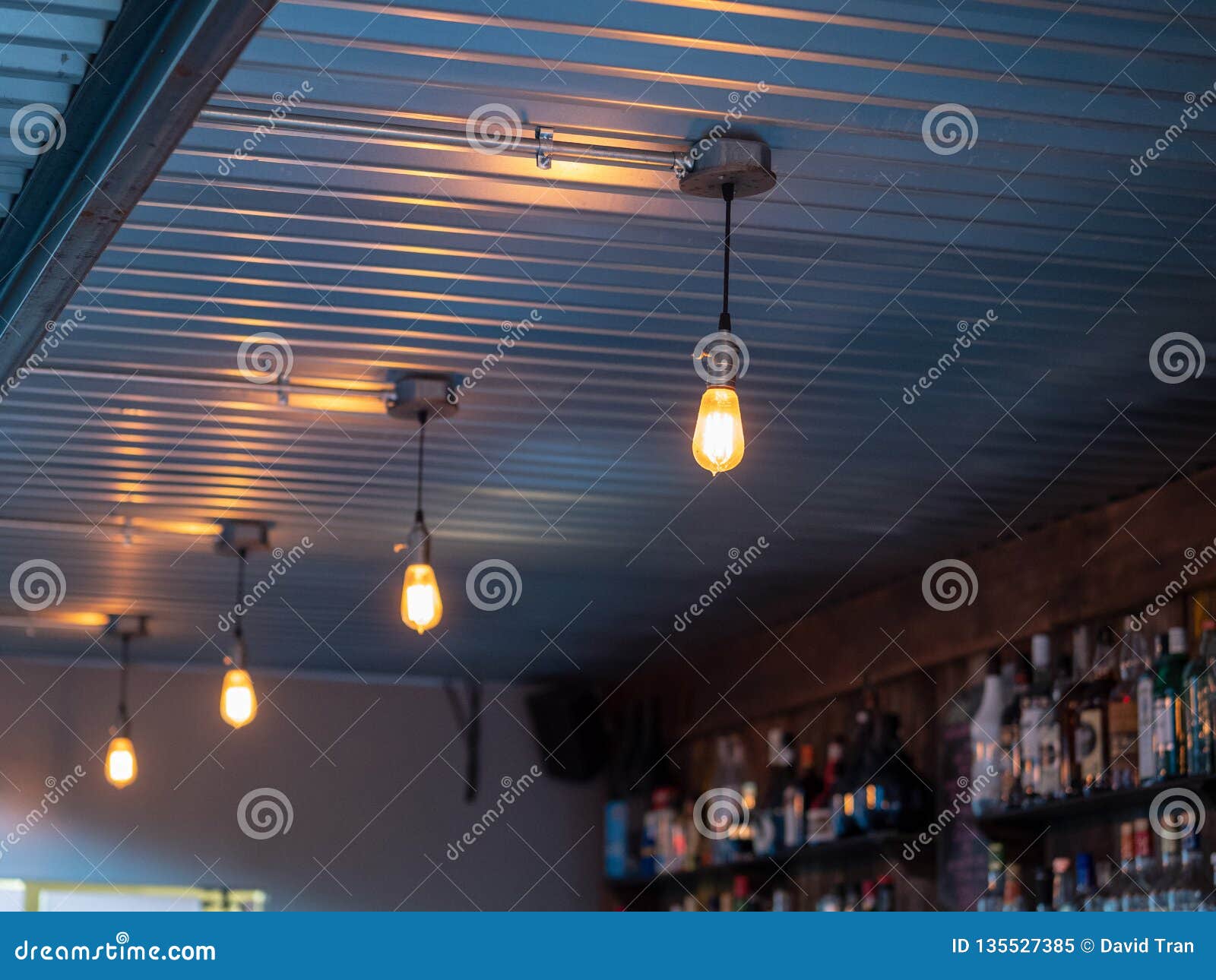 Line of Overhead Light Bulbs in an Industrial Bar Stock Image - Image ...