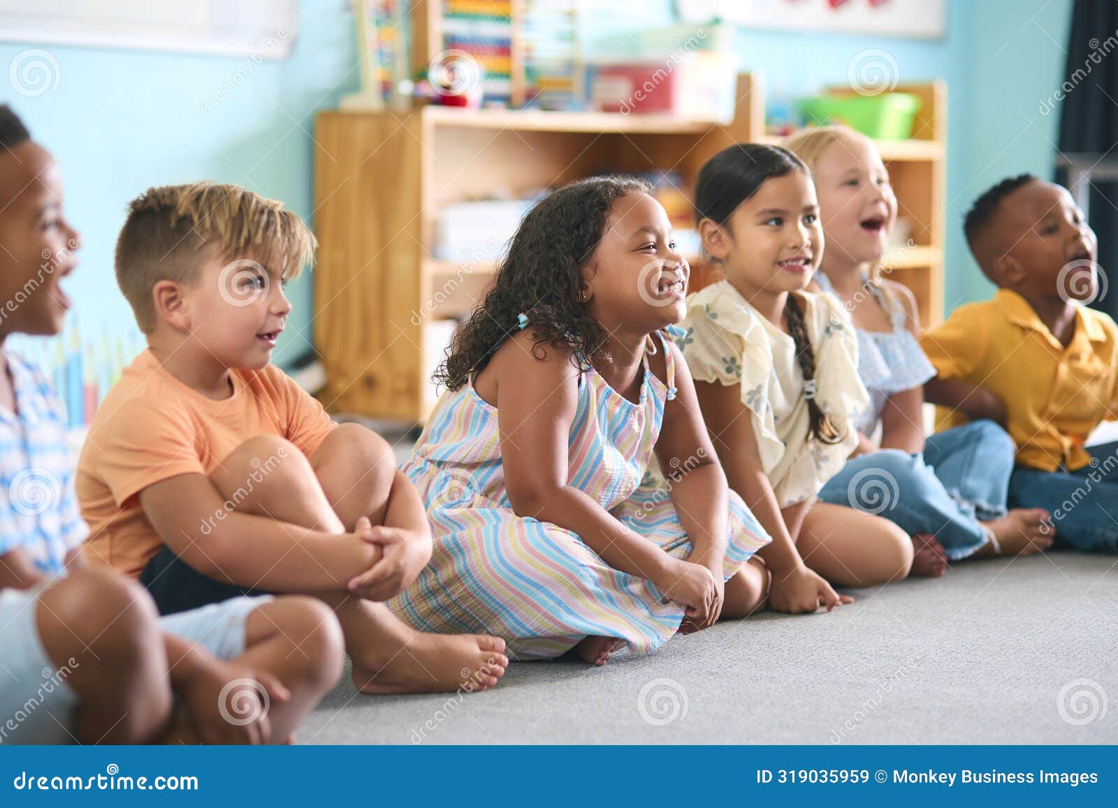 Line of Smiling Primary or Elementary School Students Sitting on Floor ...