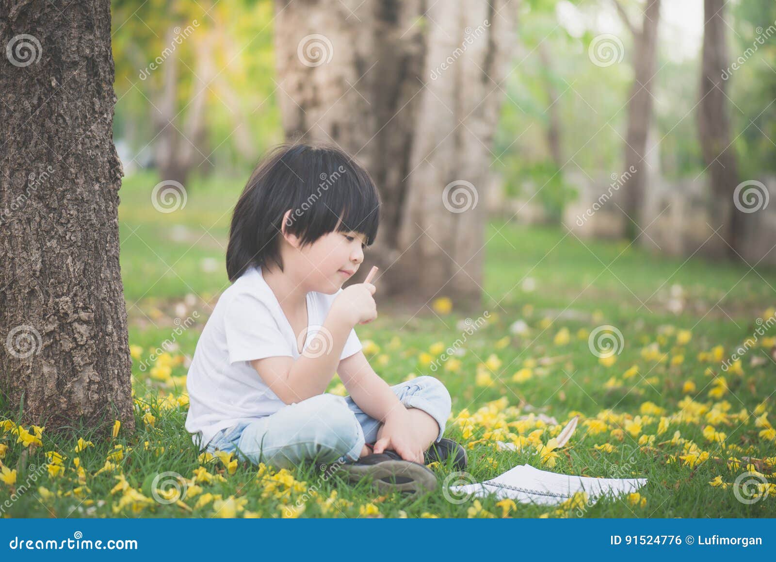 Little Asian Boy Sitting Under the Tree and Drawing in Notebook Stock ...