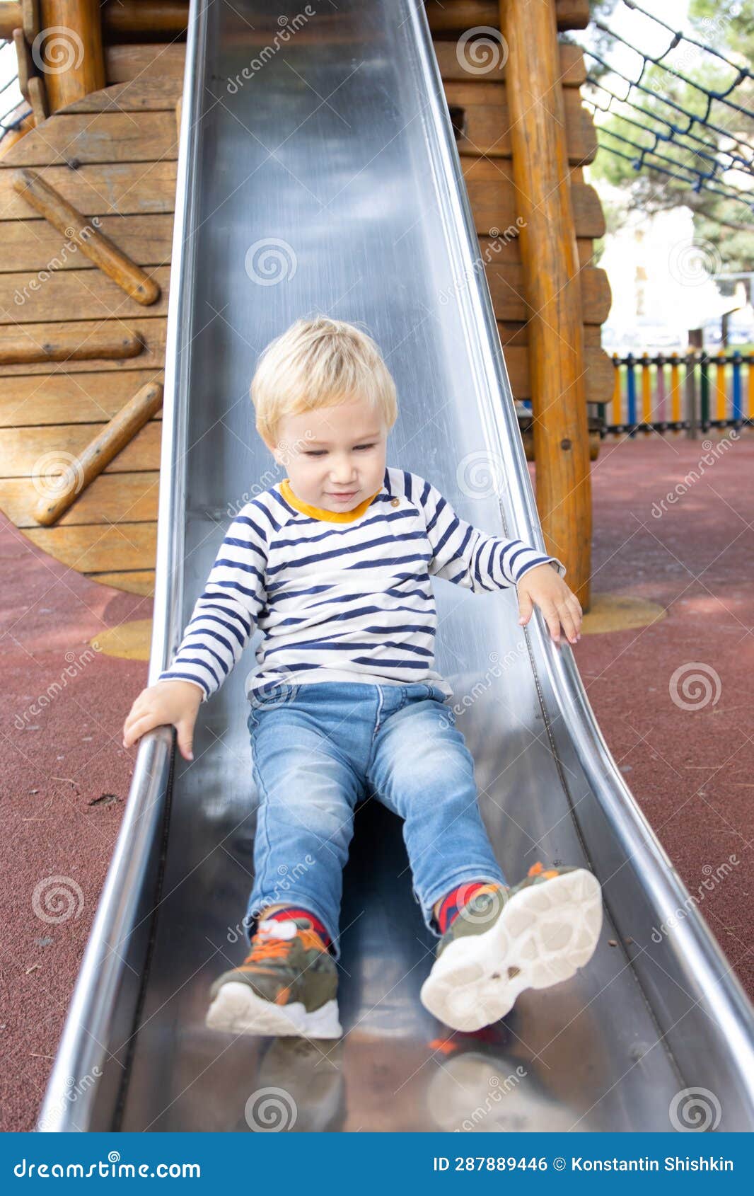 A Little Blonde Boy Slide Down a Slide on the Playground Stock Photo ...