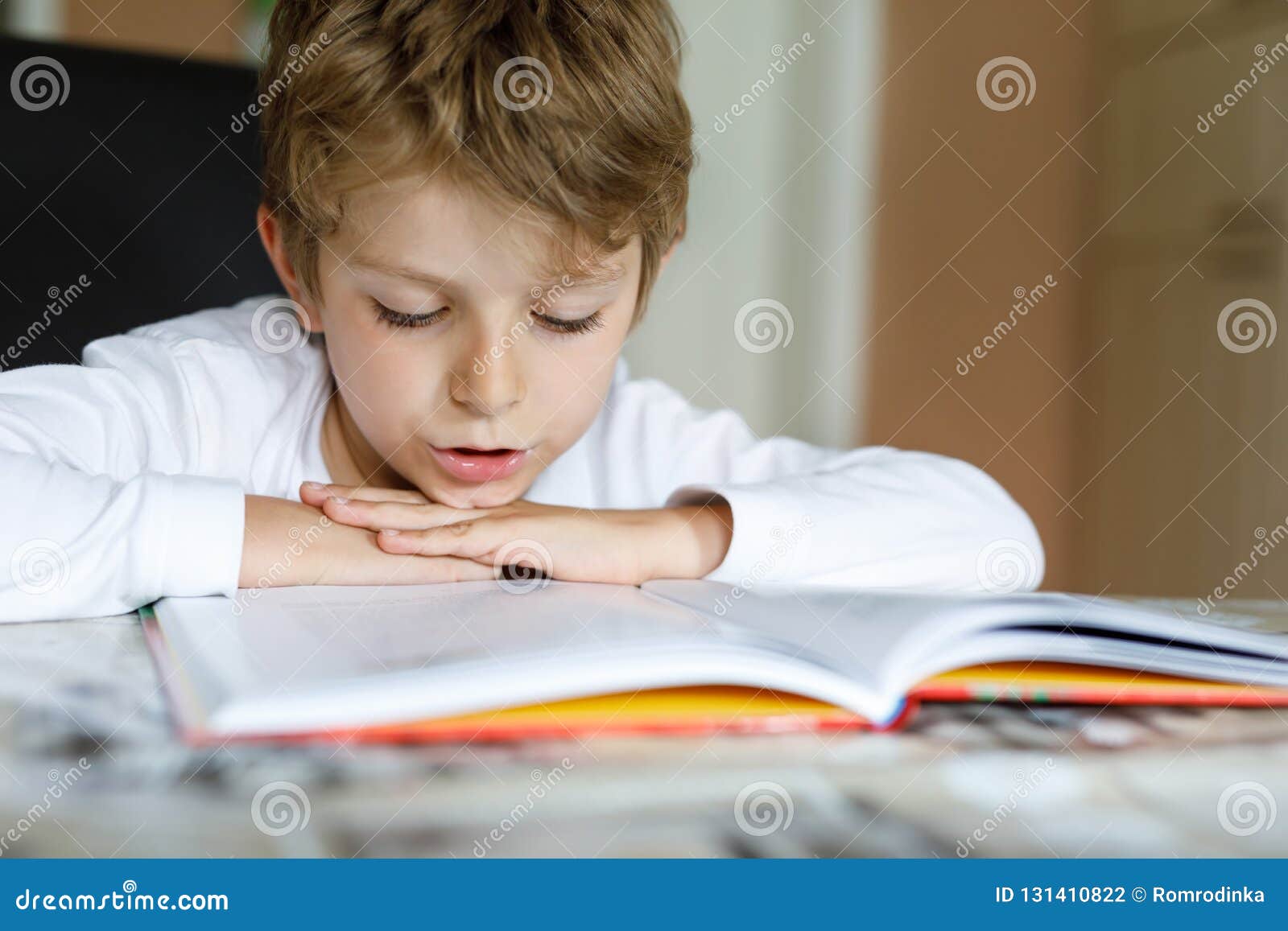 Little Blonde School Kid Boy Reading a Book at Home. Child Interested ... Little Blonde School Kid Boy Reading a Book at Home. Child Interested ...
