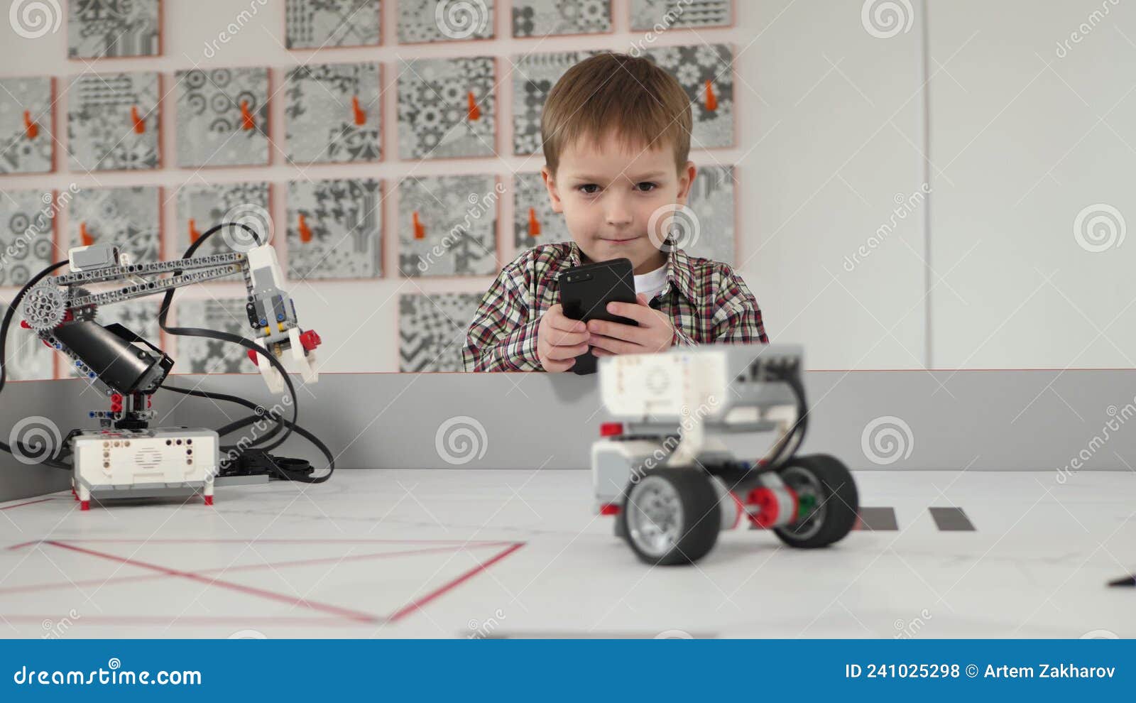Little Boy Controls a Robot Using His Phone in a Robotics Class Stock ...