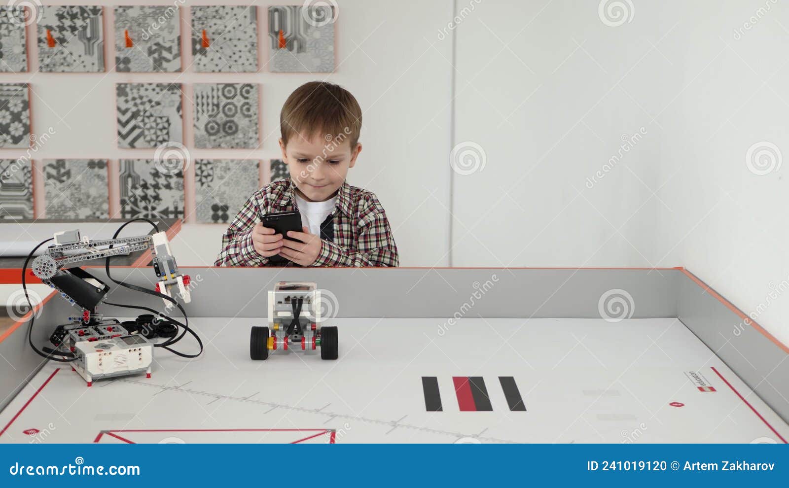 Little Boy Controls a Robot Using His Phone in a Robotics Class Stock ...