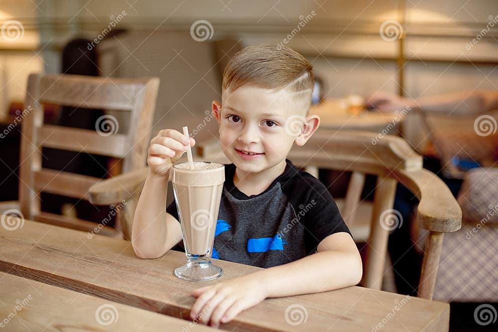 Little Boy Drinking Milkshake Sitting at the Table in Cafe Stock Photo ...